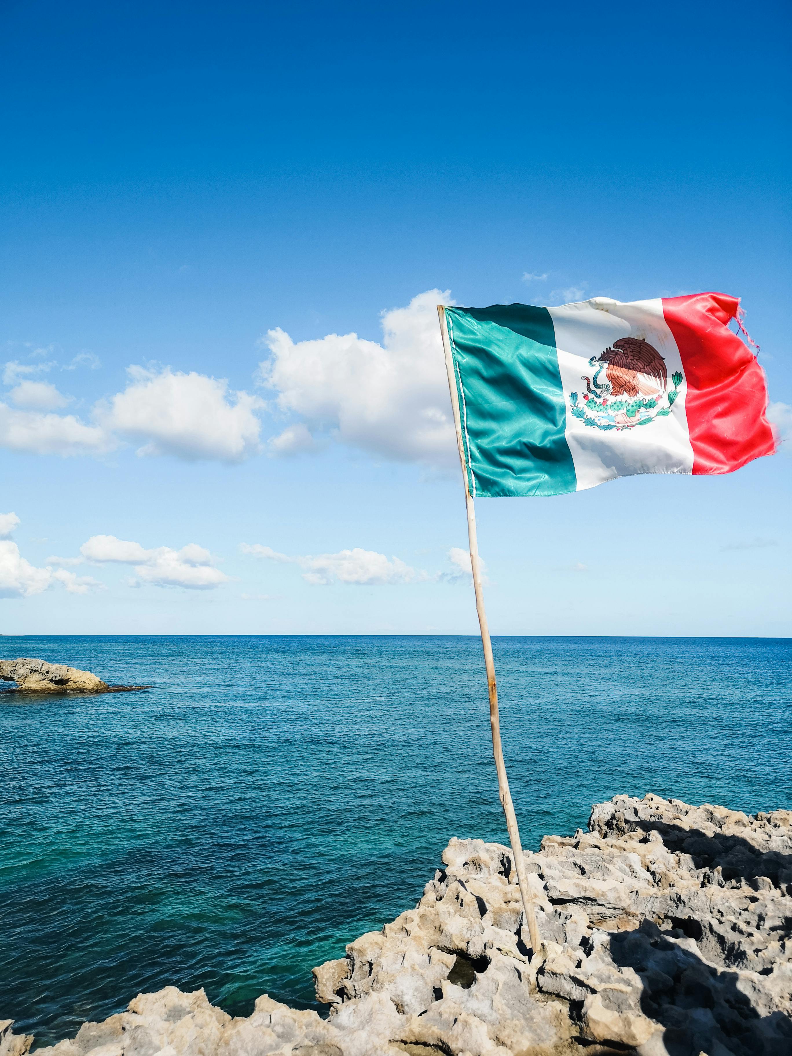 Flag of Mexico on Rocks on Sea Shore · Free Stock Photo