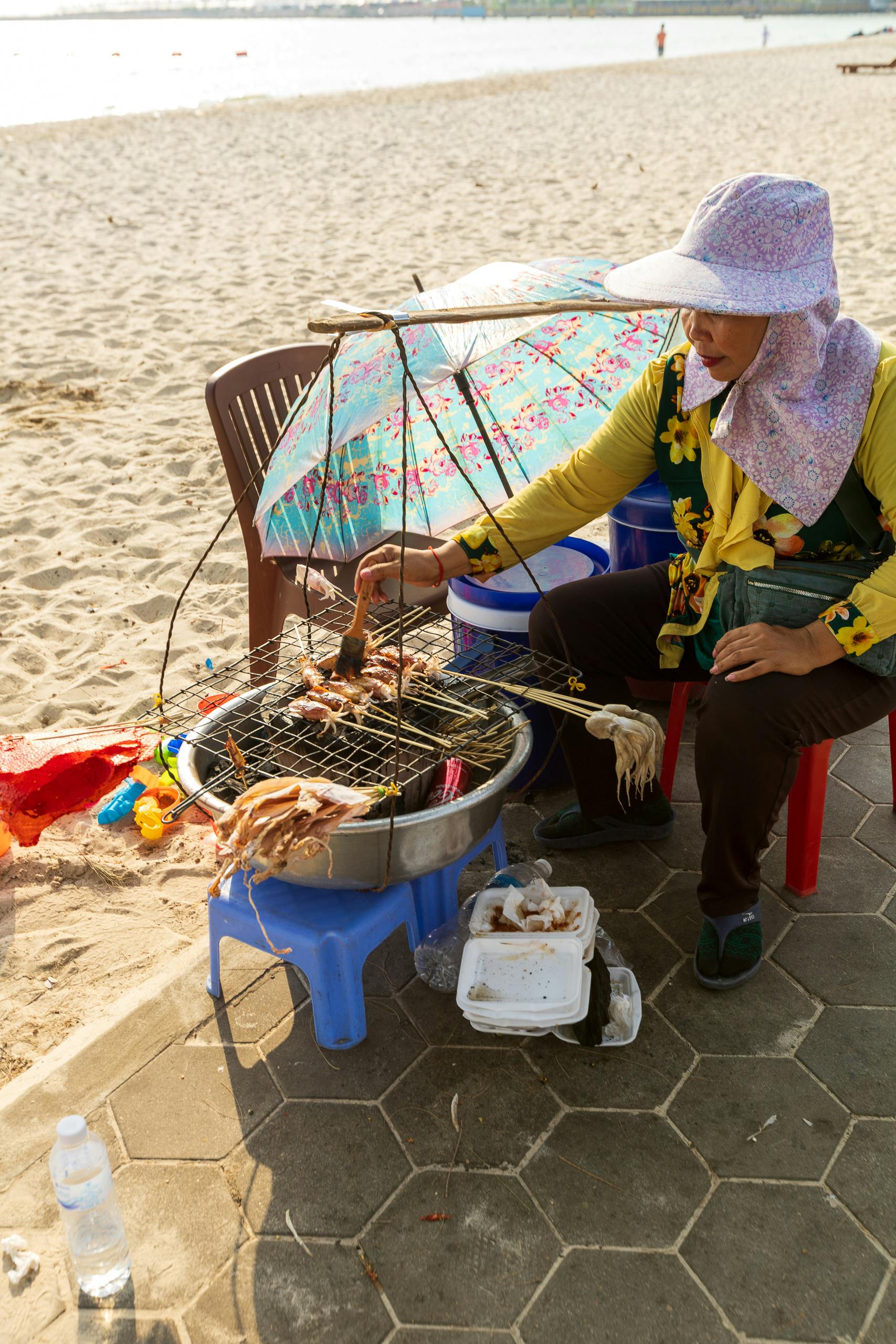 Photo of a Woman Cooking on a Sandy Beach · Free Stock Photo