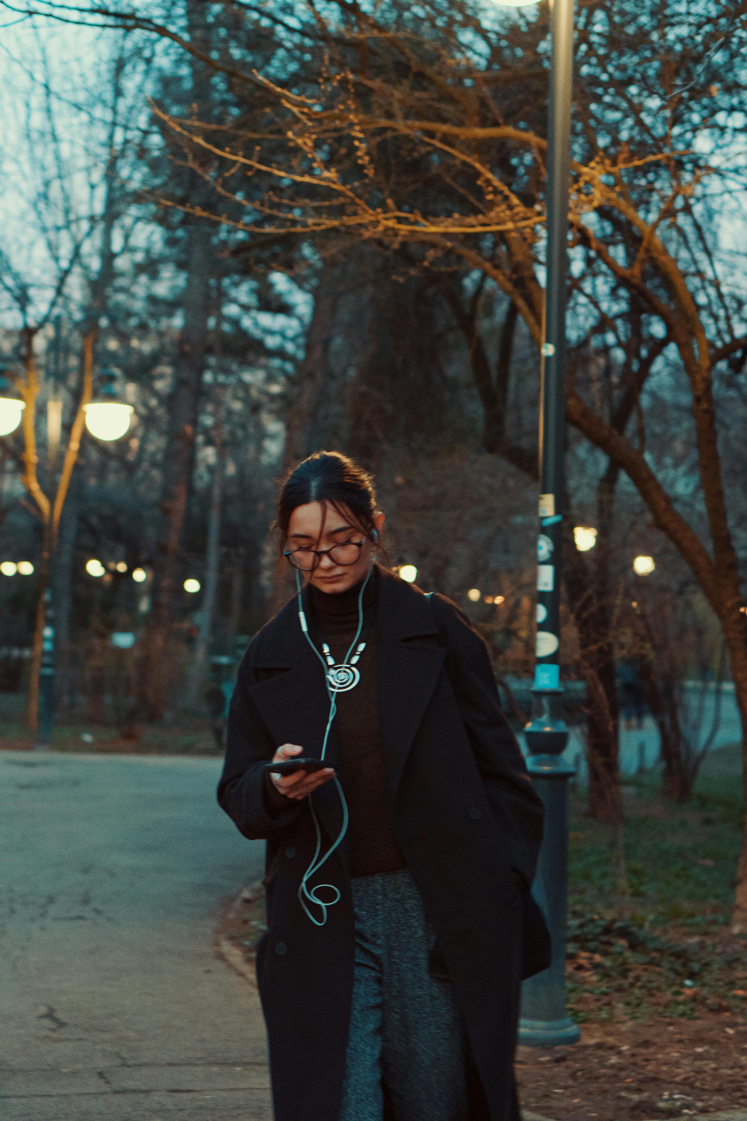 Photo of a Brunette Woman Using a Smart Phone with Air Pods in a Park ...