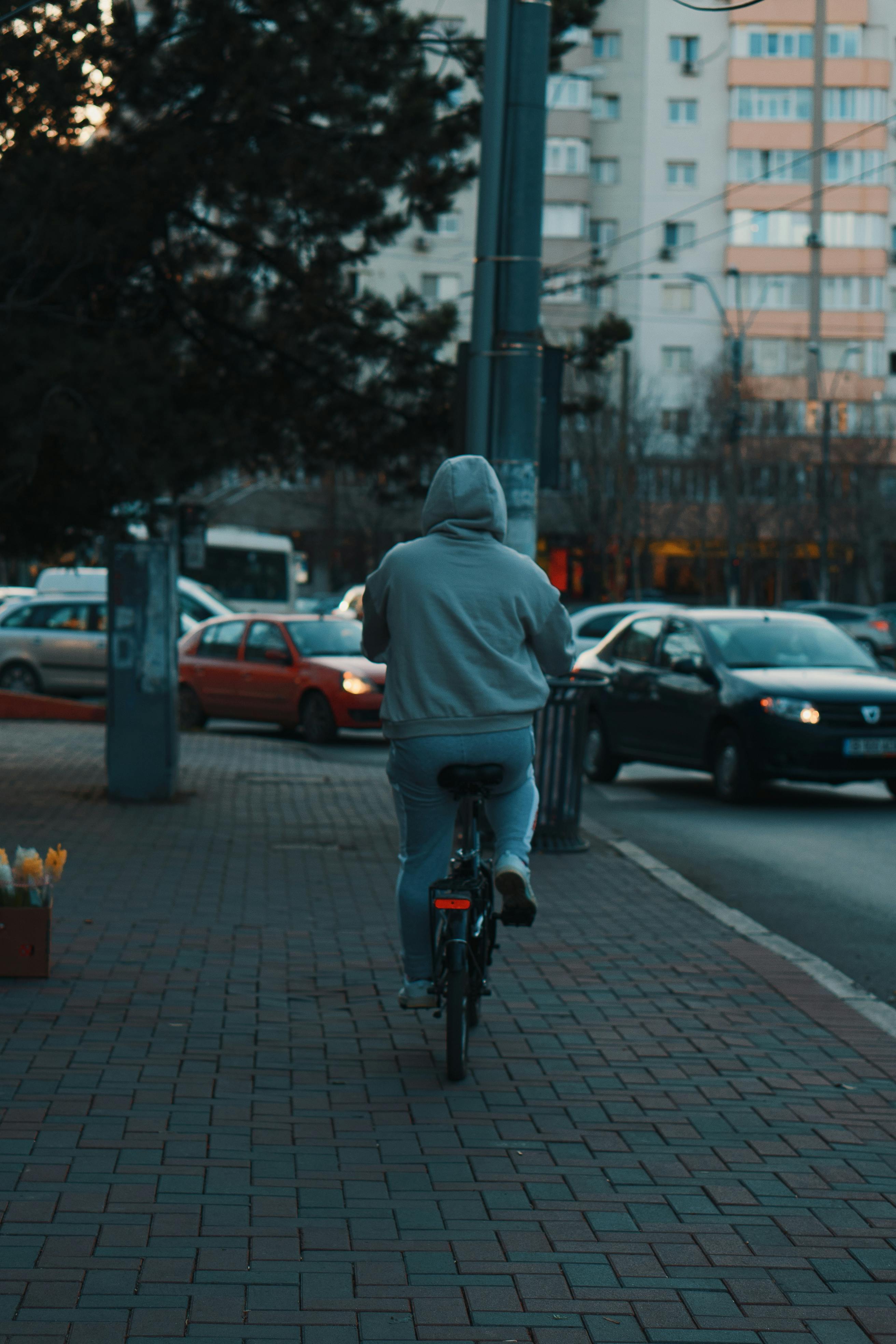 Back View of a Cyclist Wearing a Hood, Riding on a Pavement · Free ...