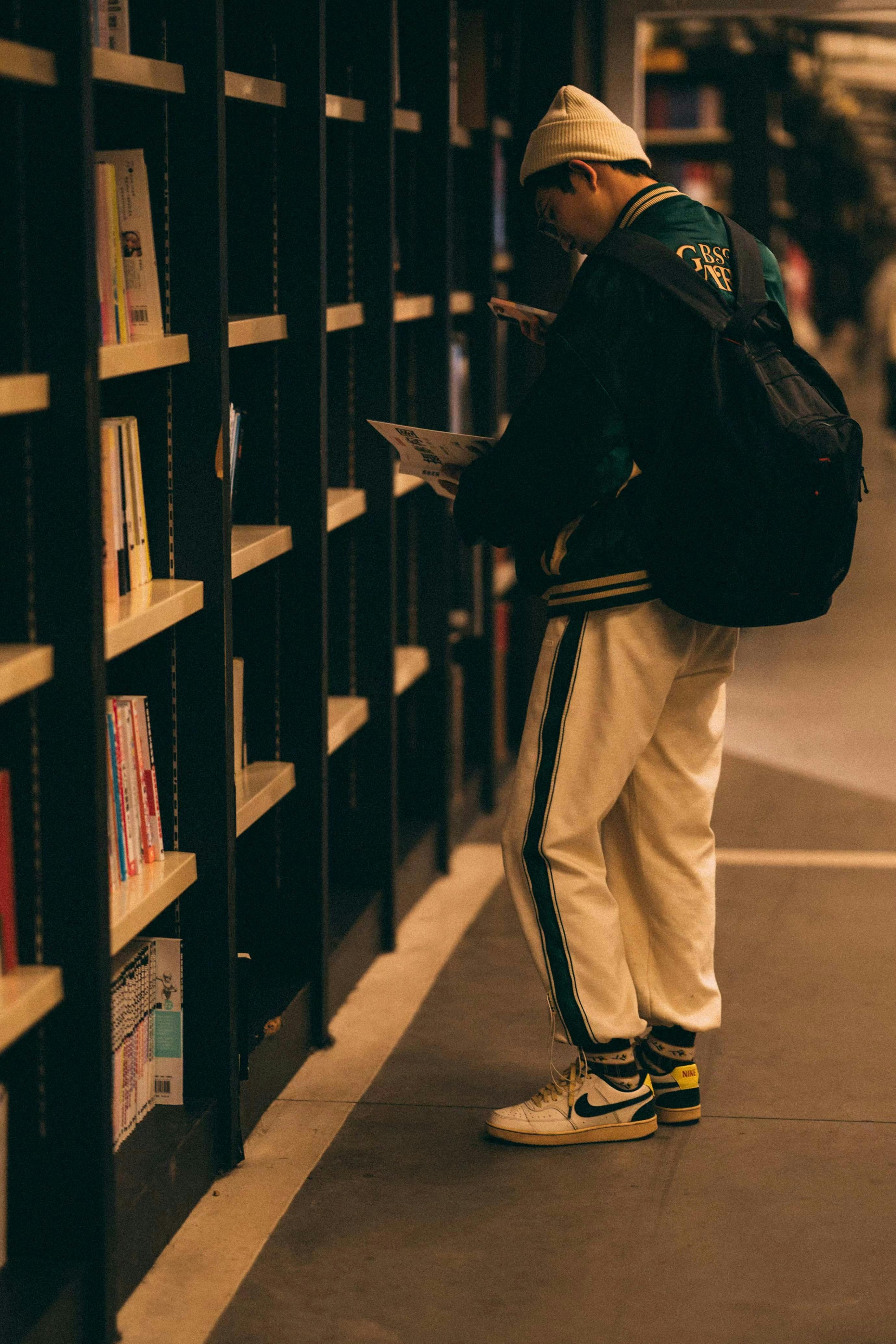Black student against various literature on bookshelves · Free Stock Photo