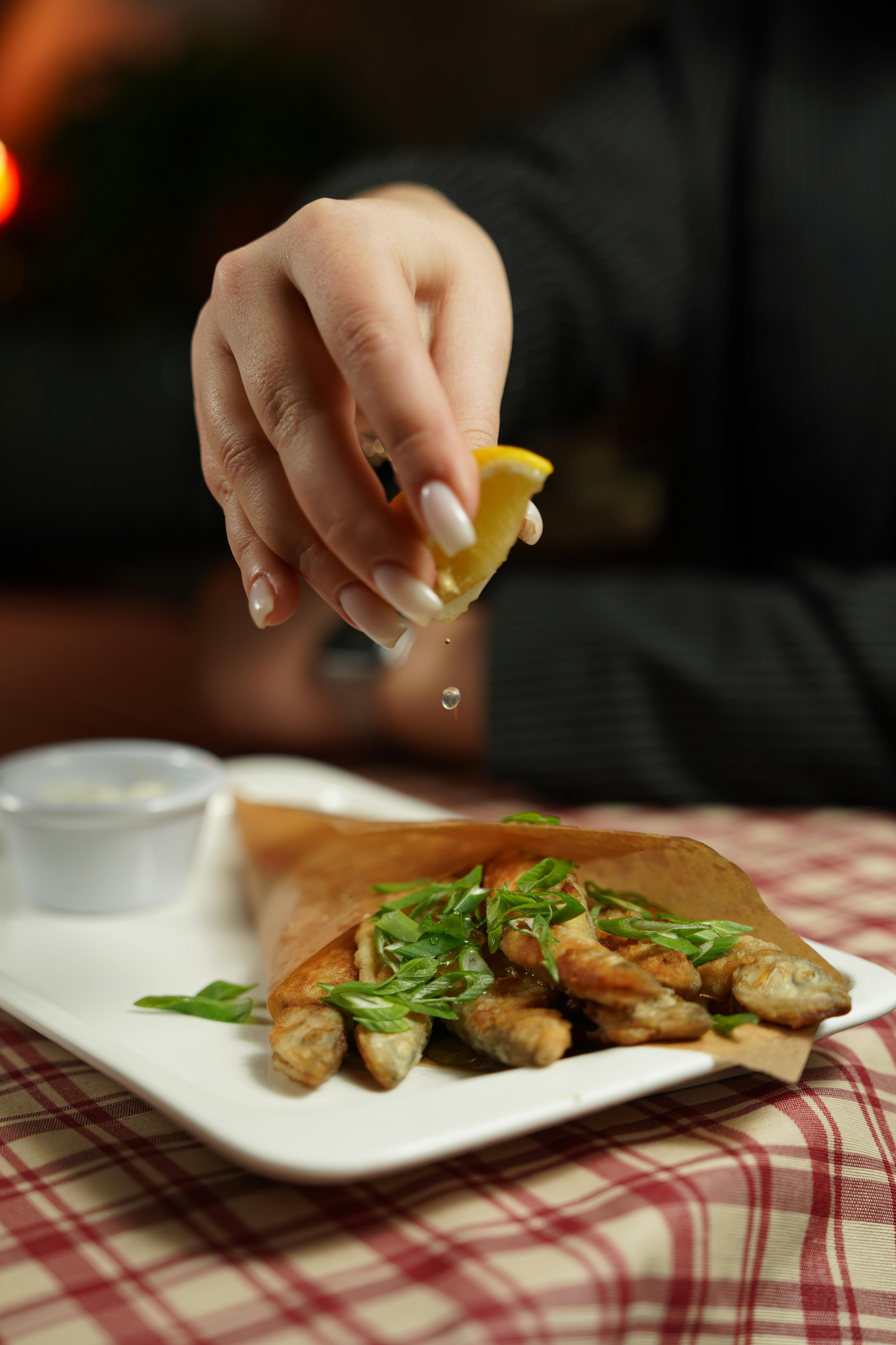Woman Dripping Lemon Juice on Fried Fish · Free Stock Photo