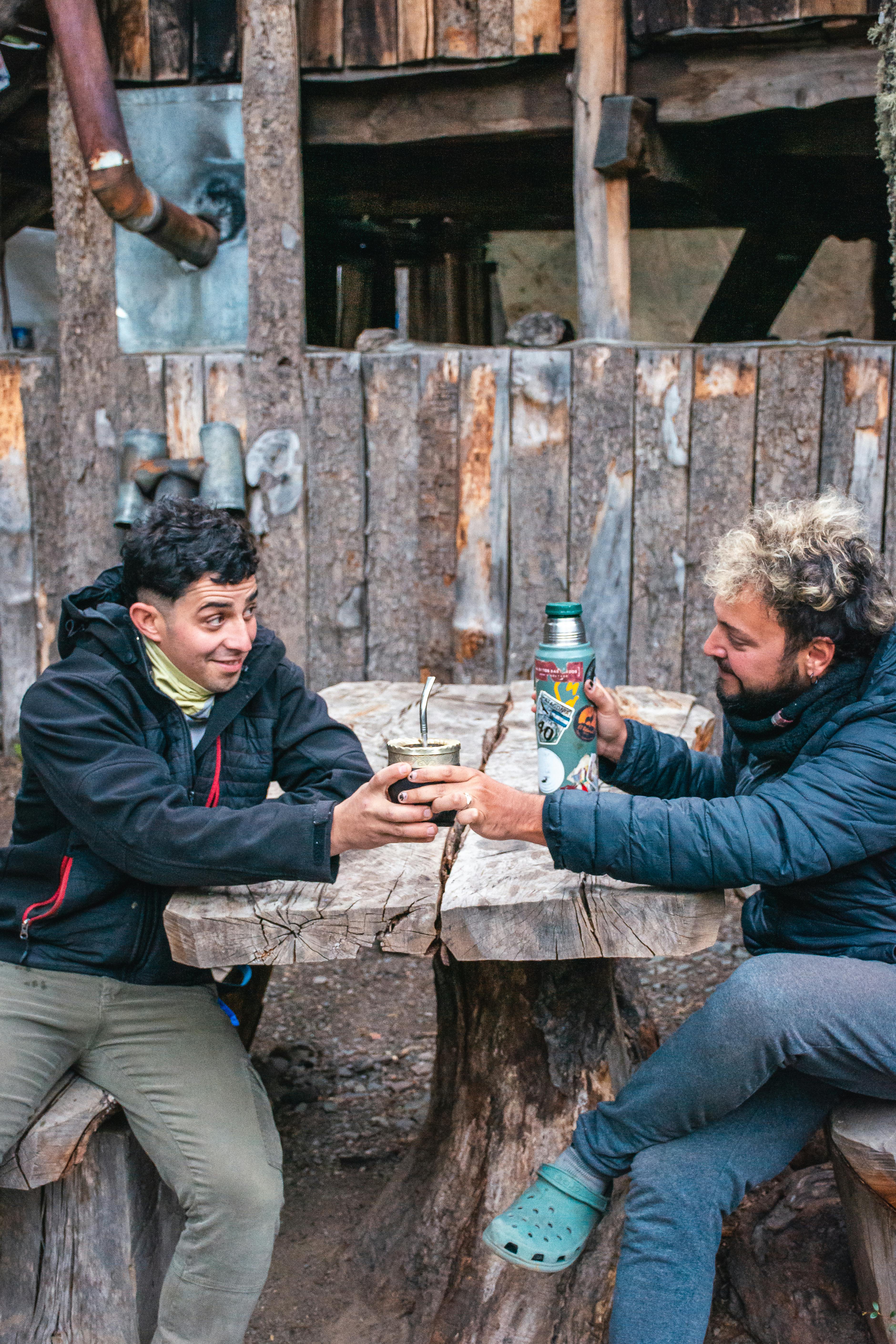 Men Sitting at a Wooden Table during a Break from Hiking and Sharing a ...