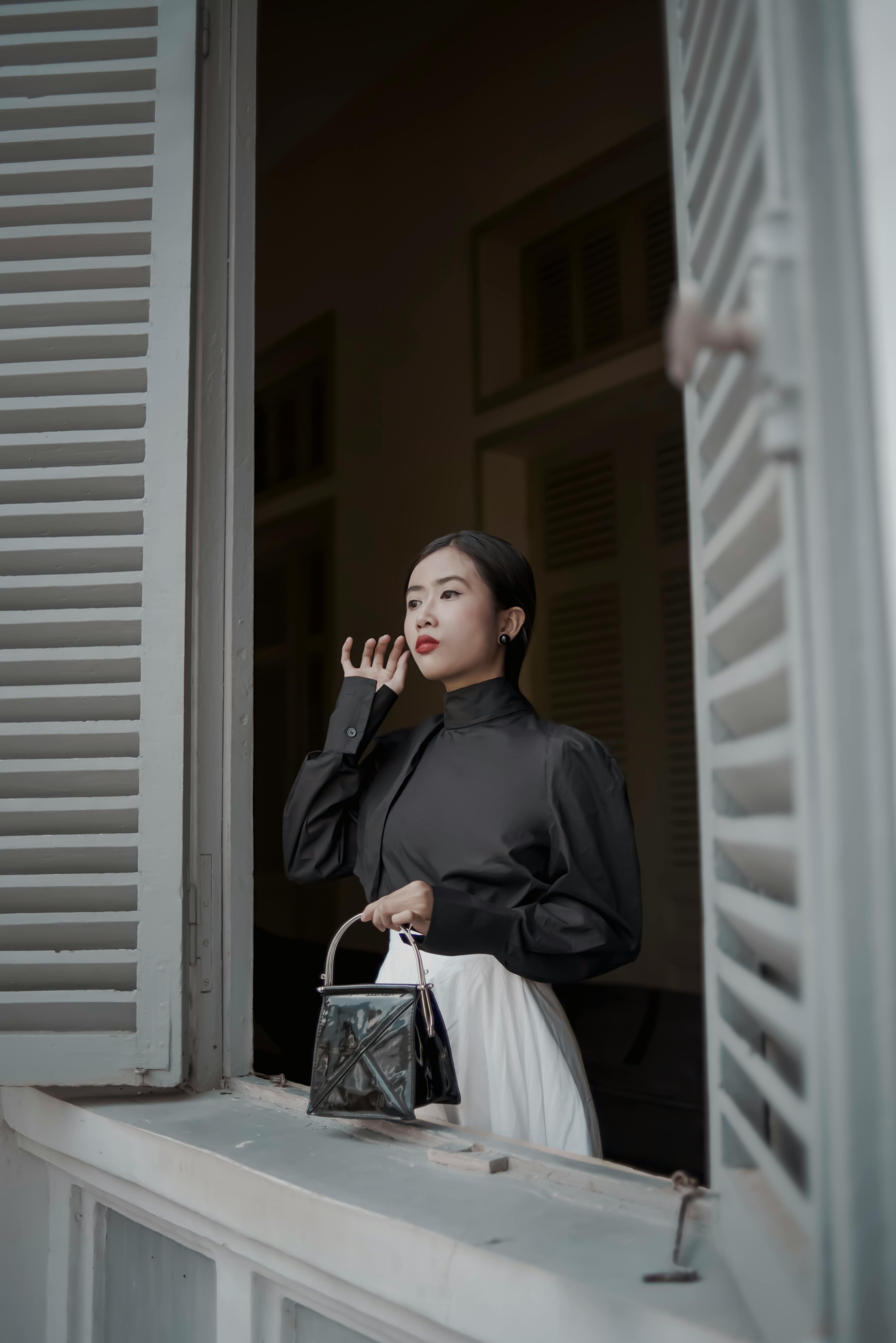 Beautiful Woman with Handbag Standing in Window · Free Stock Photo