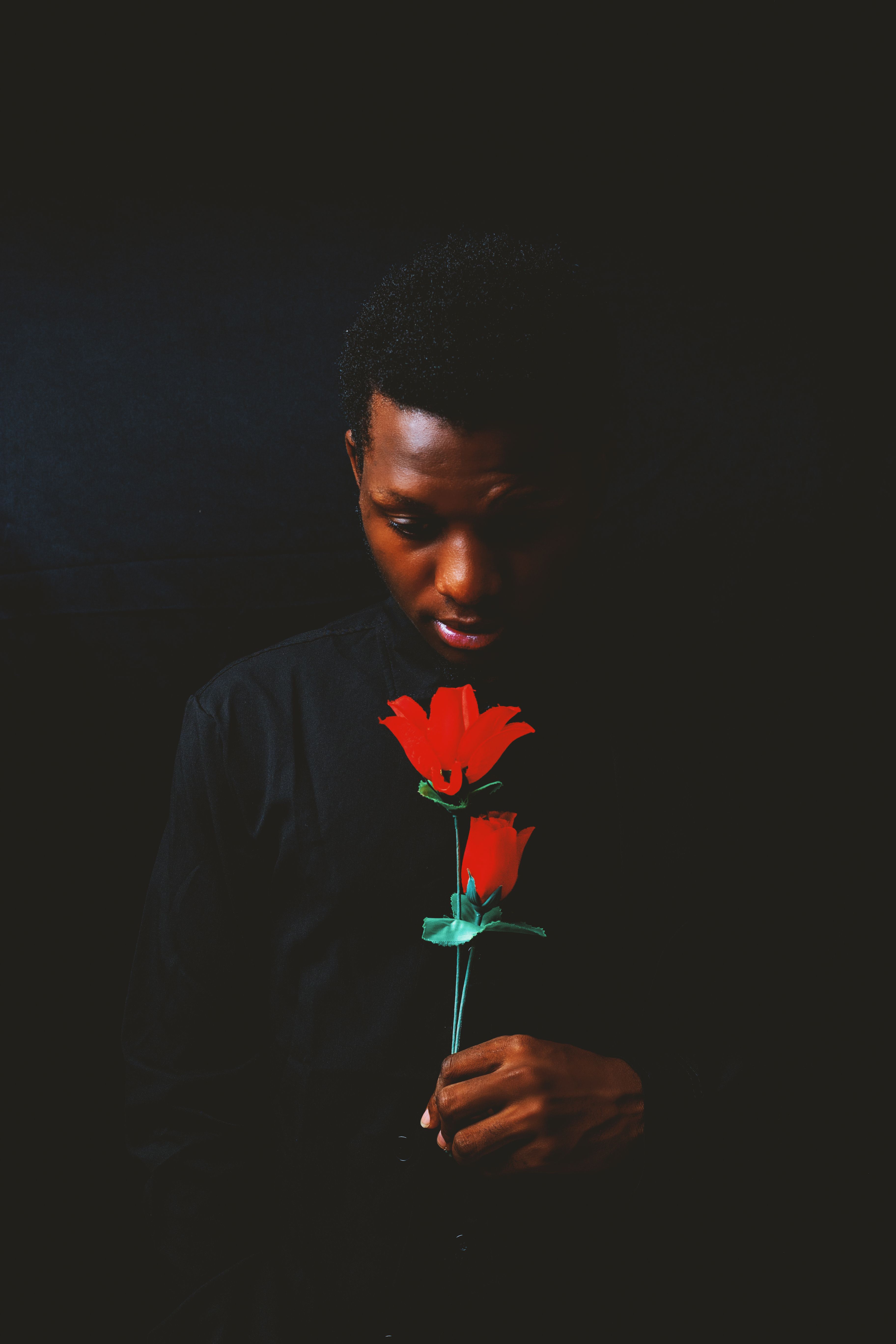 Dark Photo of a Sad Man Holding a Red Flower · Free Stock Photo