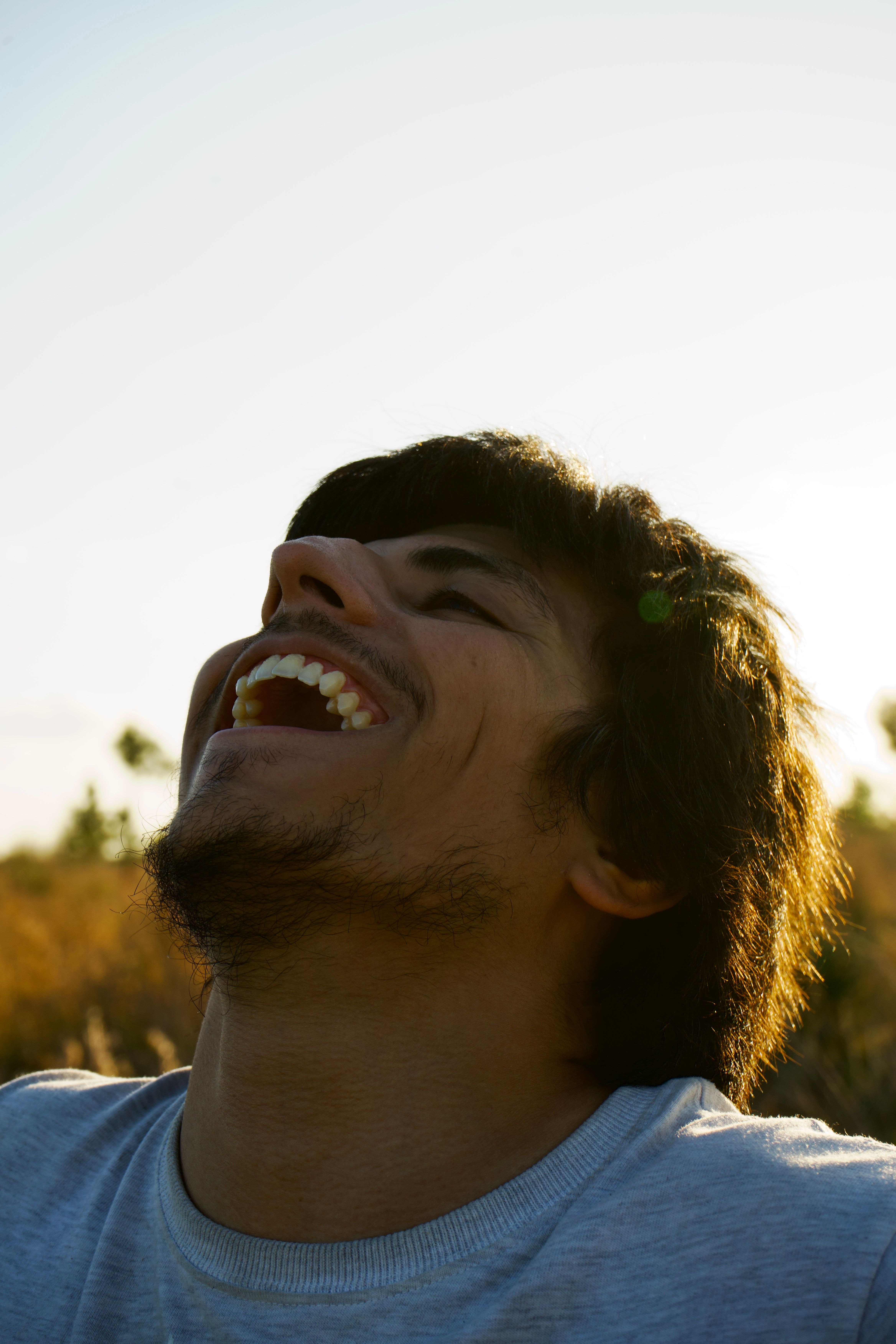 Young Man Standing Outside, Throwing His Head Back and Smiling · Free ...