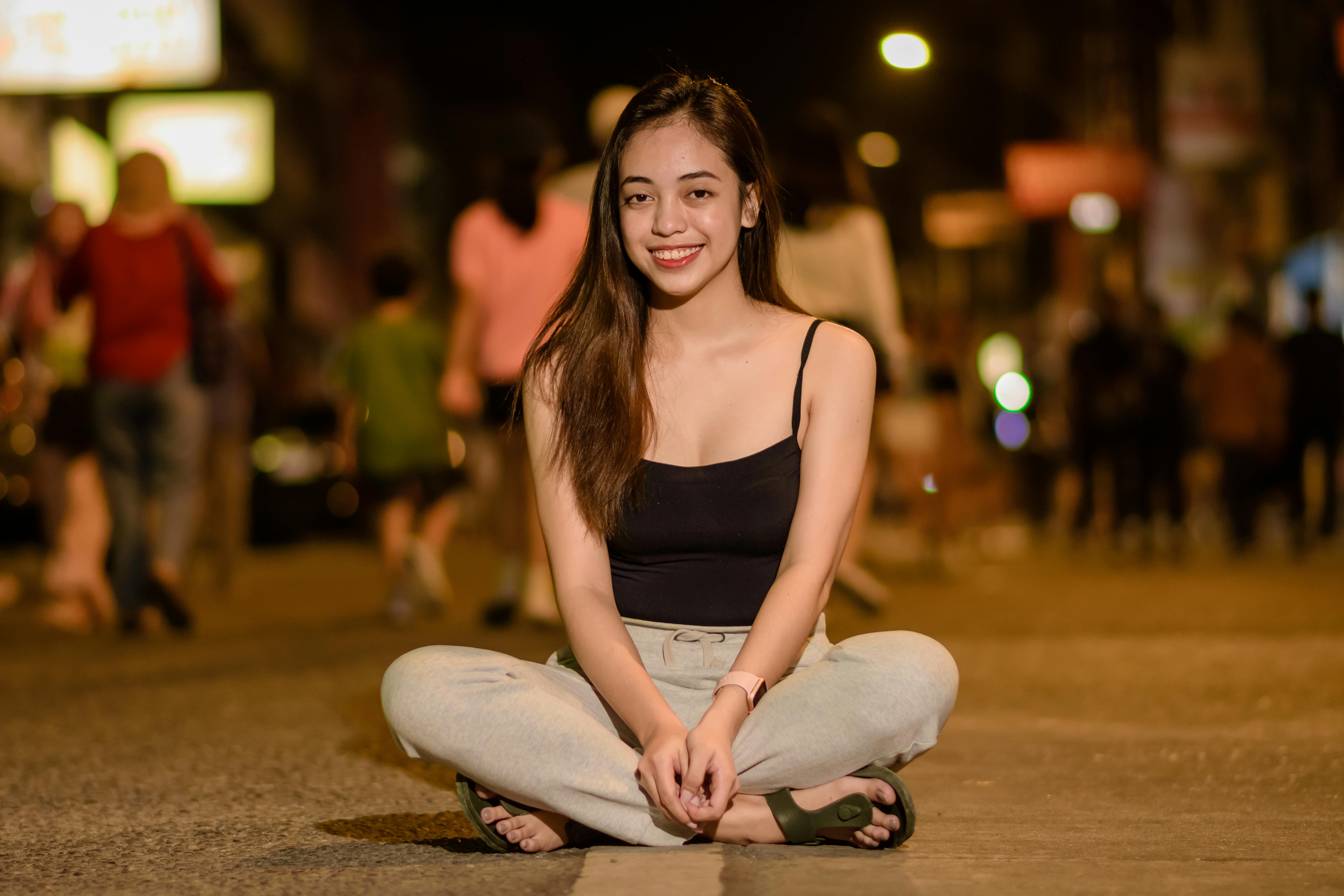 Woman Sitting and Posing on Street at Night · Free Stock Photo