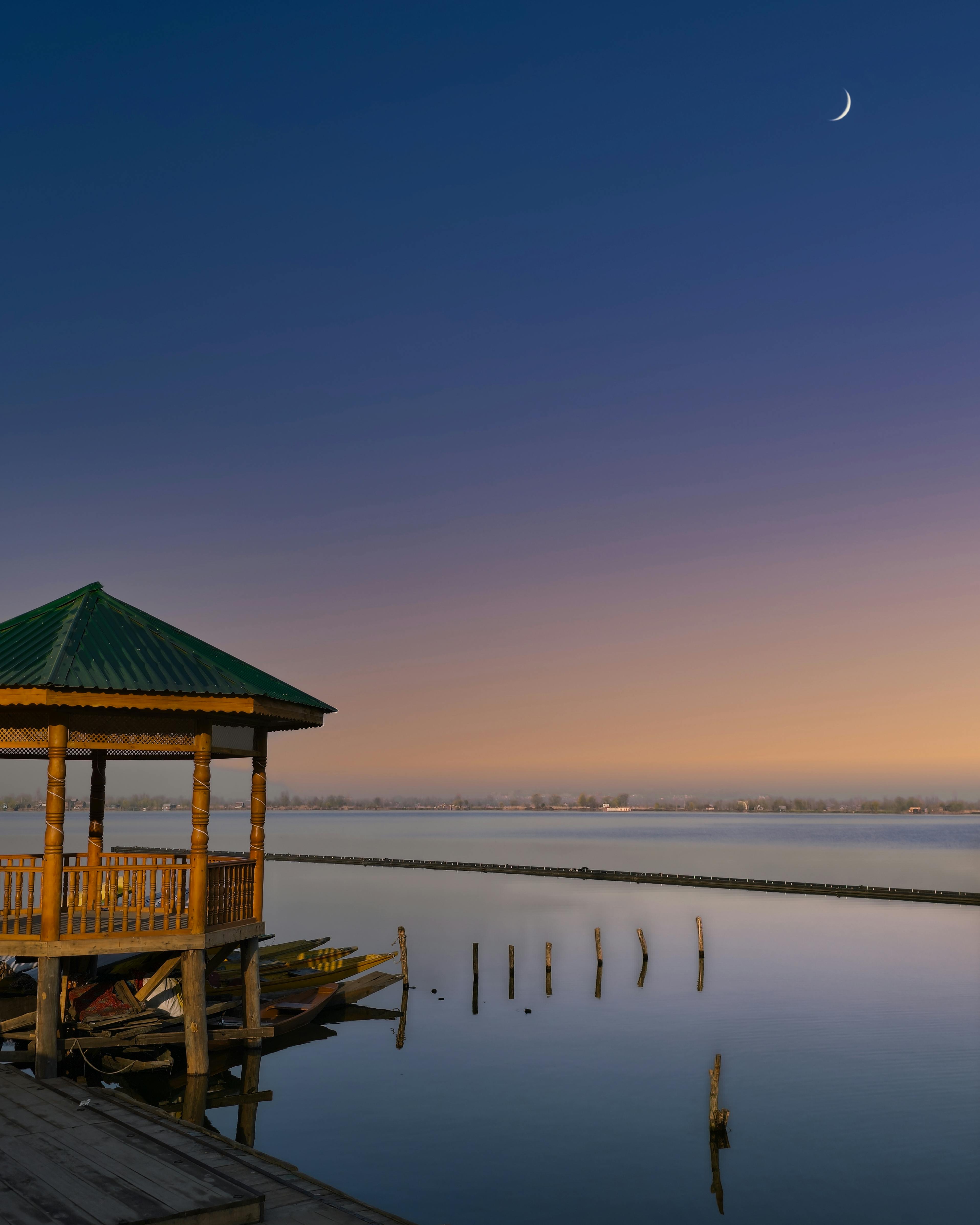 View of a Pier with a Gazebo and Body of Water at Sunset · Free Stock Photo