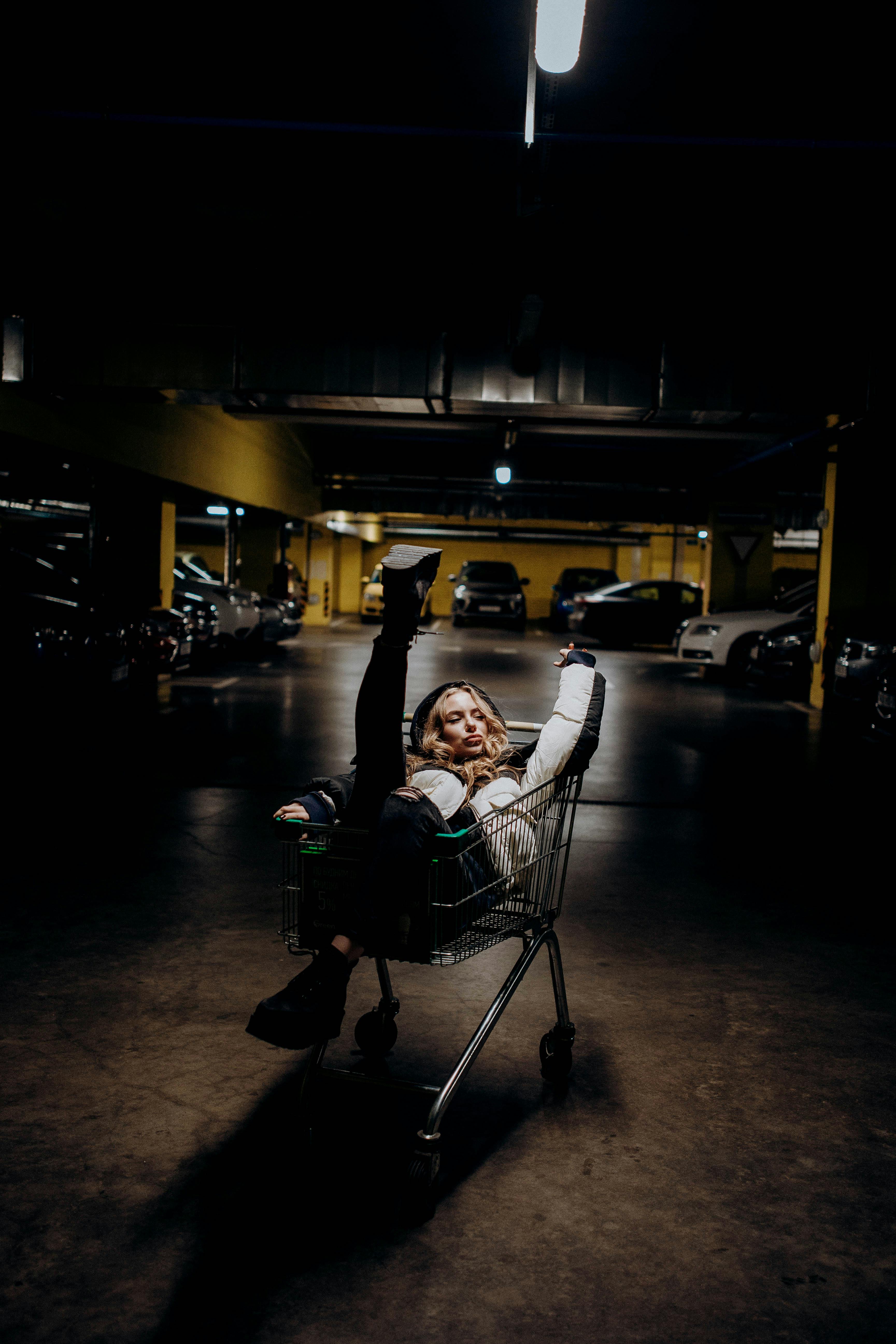 Blonde Woman in Jacket Lying Down in Shopping Cart · Free Stock Photo