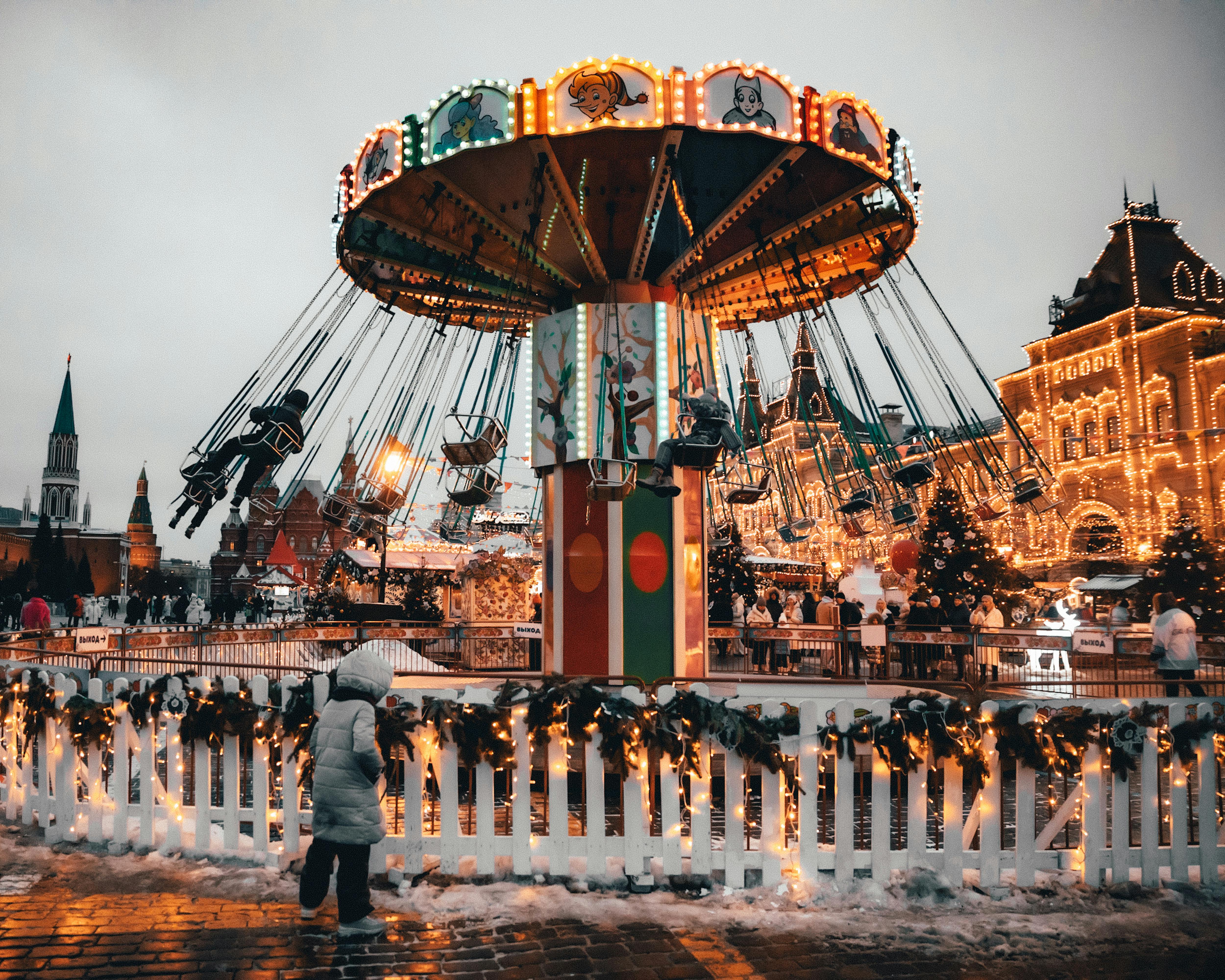 Child in Jacket Standing near Carousel in Winter · Free Stock Photo