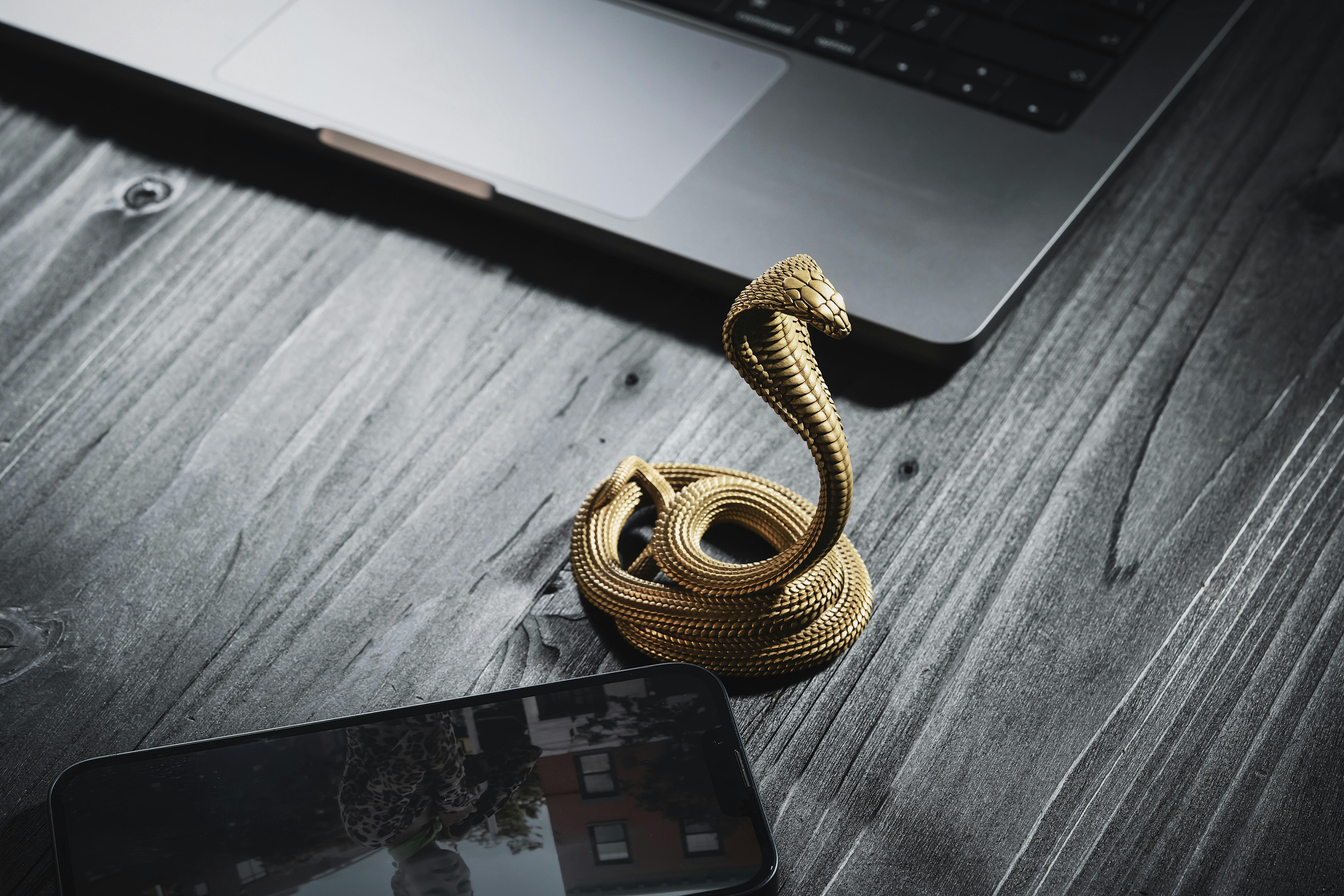 A Golden Cobra Phone Stand Standing on a Desk next to a Laptop and ...