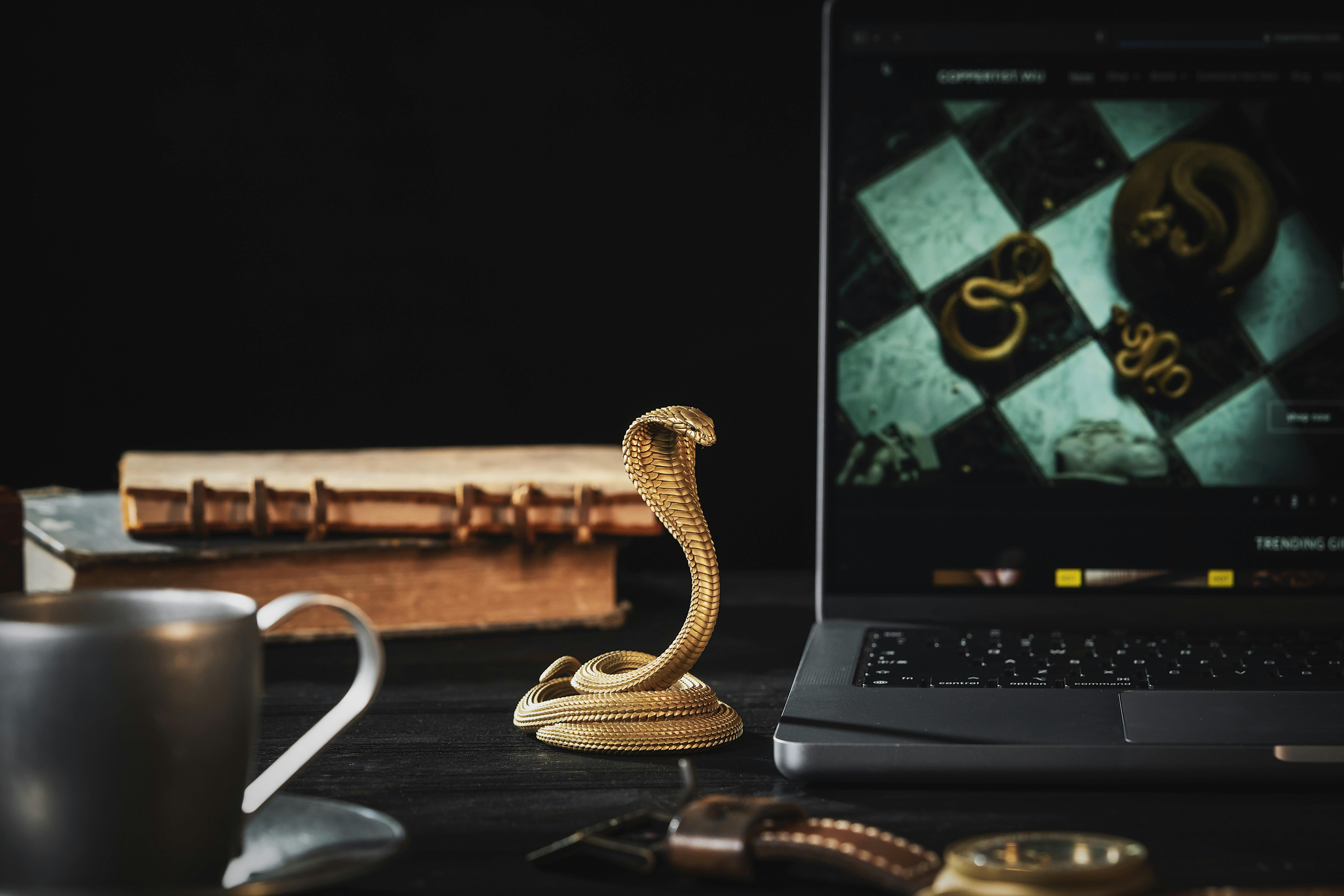 A Handmade, Golden Cobra Phone Stand Standing next to a Laptop · Free ...