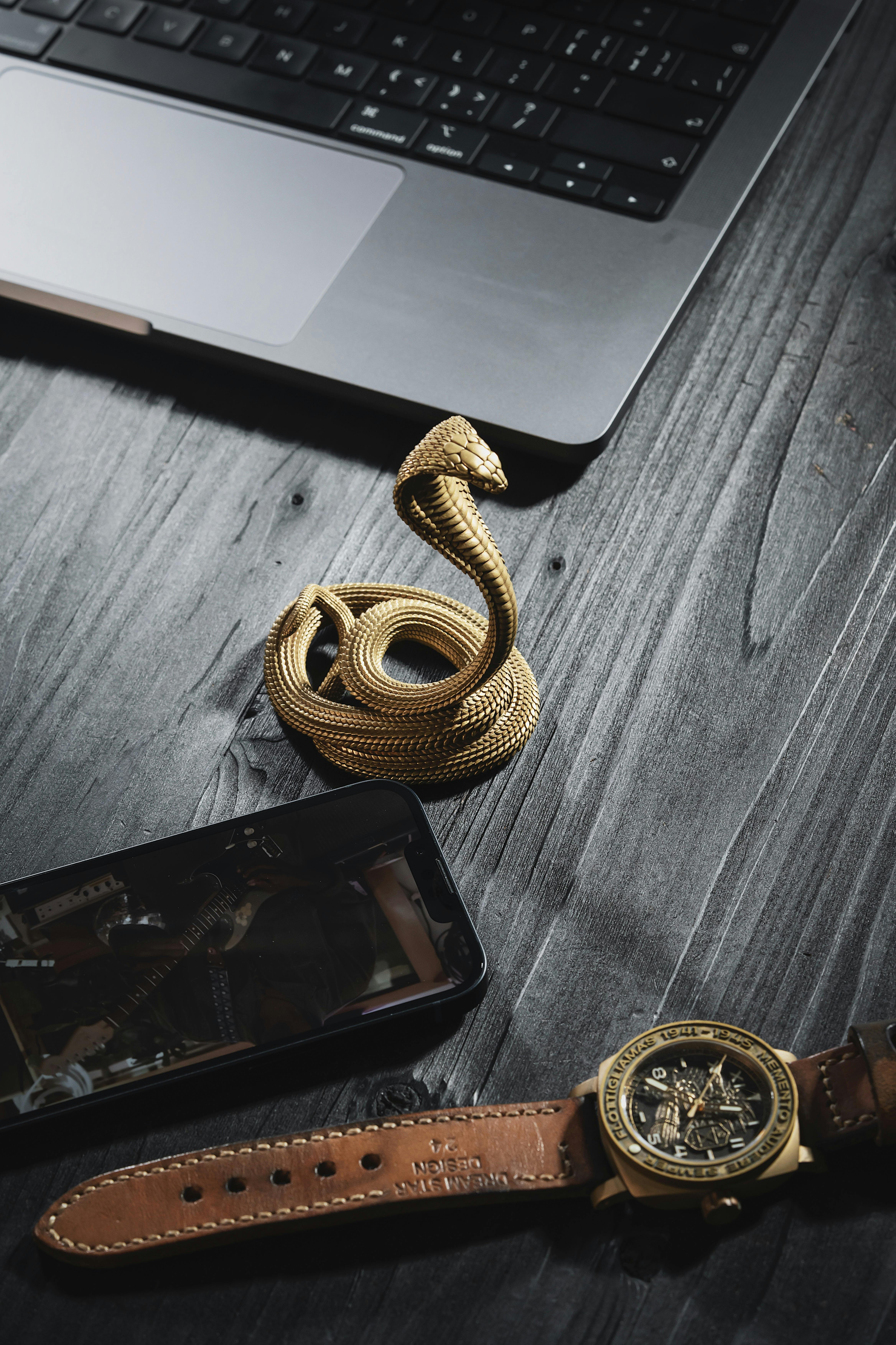 A Handmade, Golden Cobra Phone Stand Standing next to a Smartphone ...