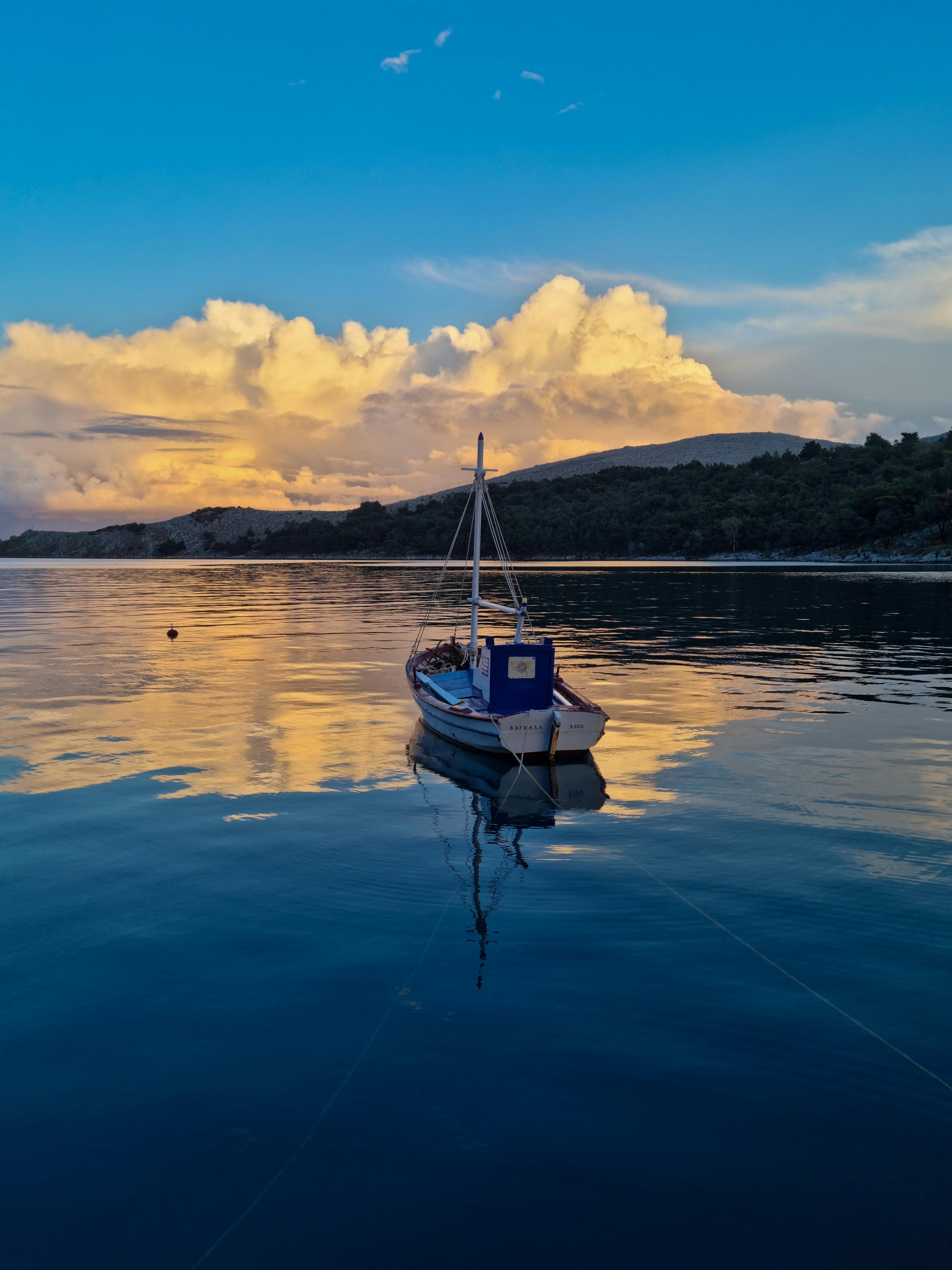 A boat is floating in the water with clouds in the sky · Free Stock Photo
