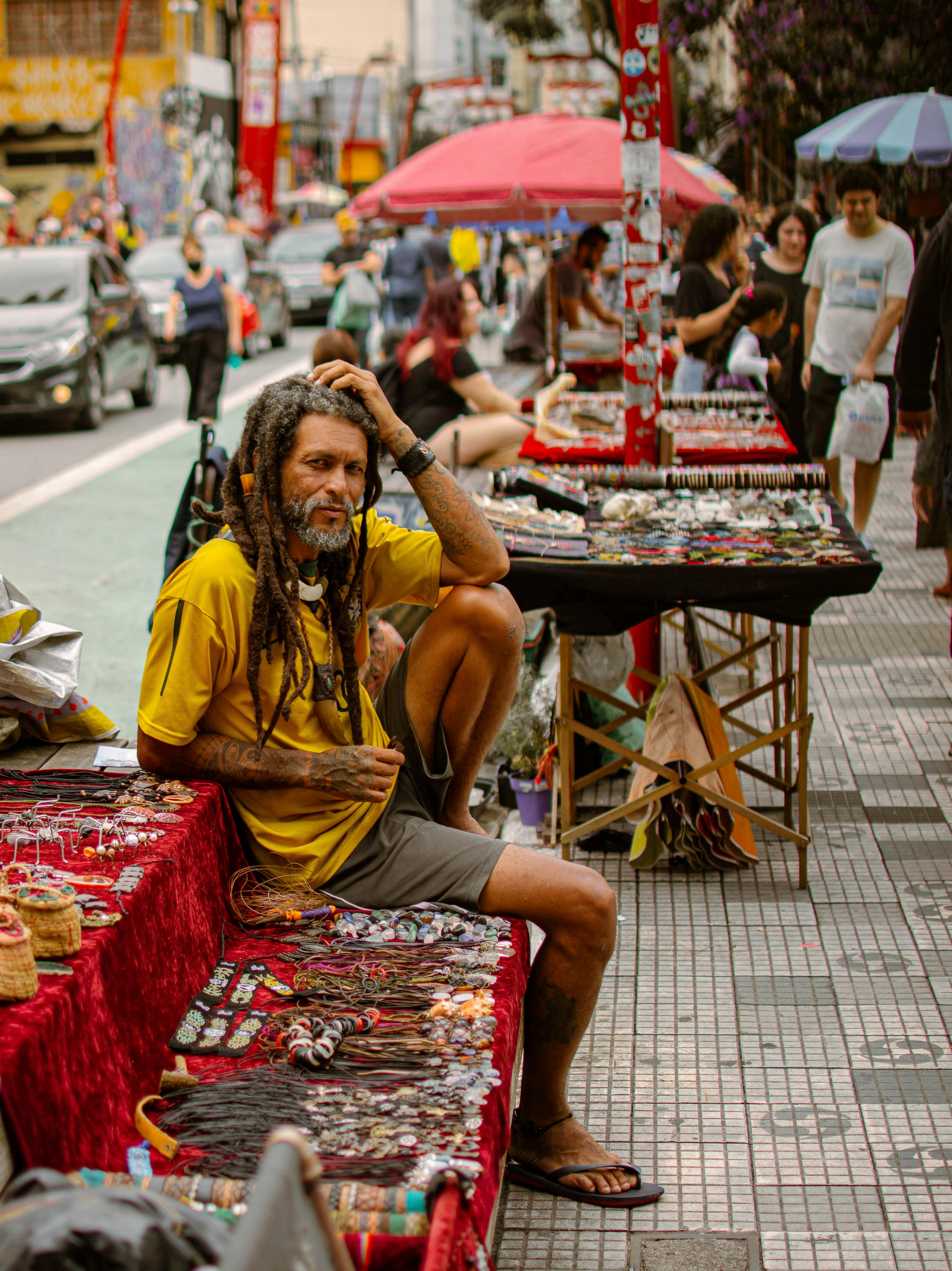Man with Dreadlocks at a Street Stall with Pendants on Leather Strings ...