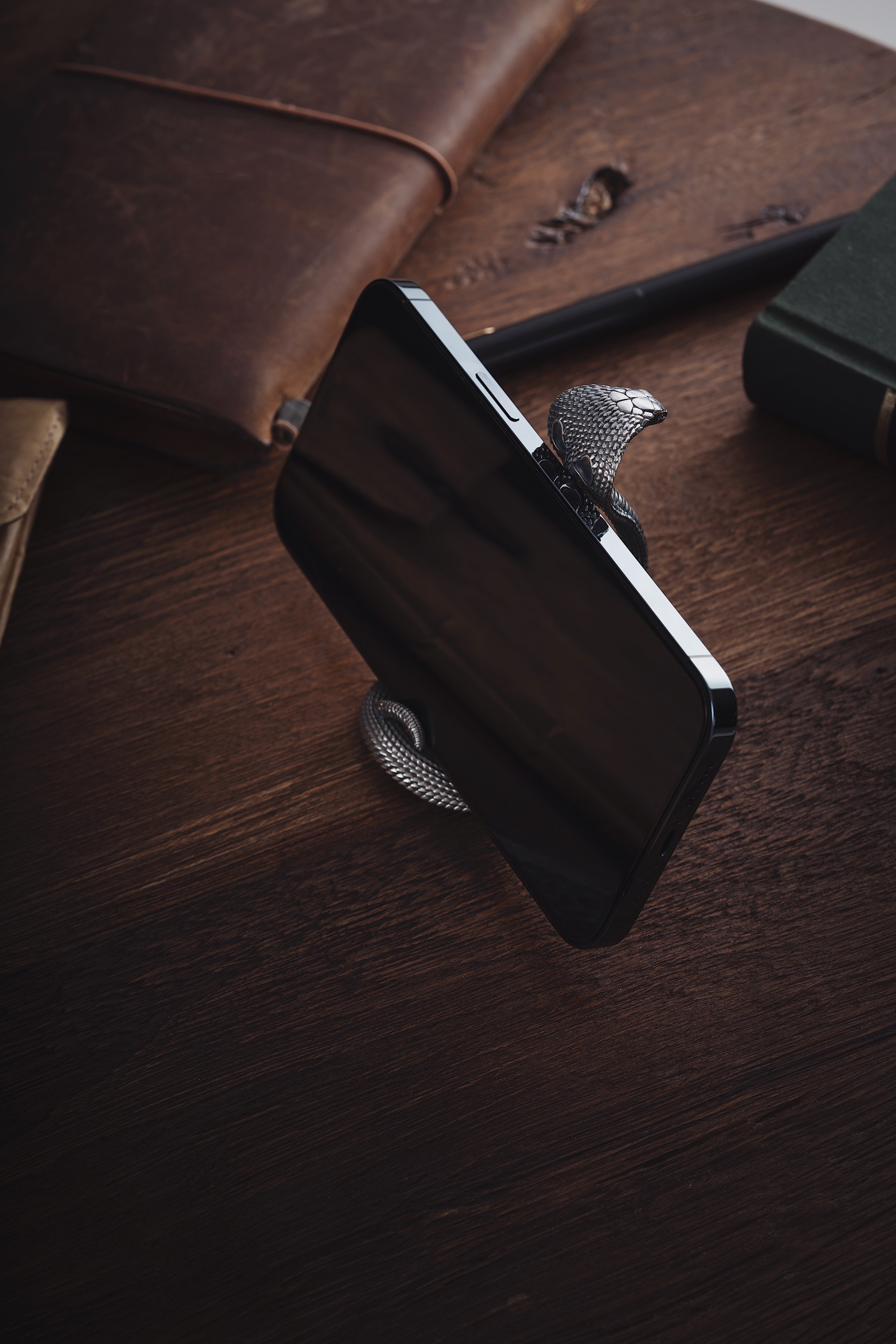Oxidized Silver Snake-shaped Phone Stand with an iPhone next to a ...