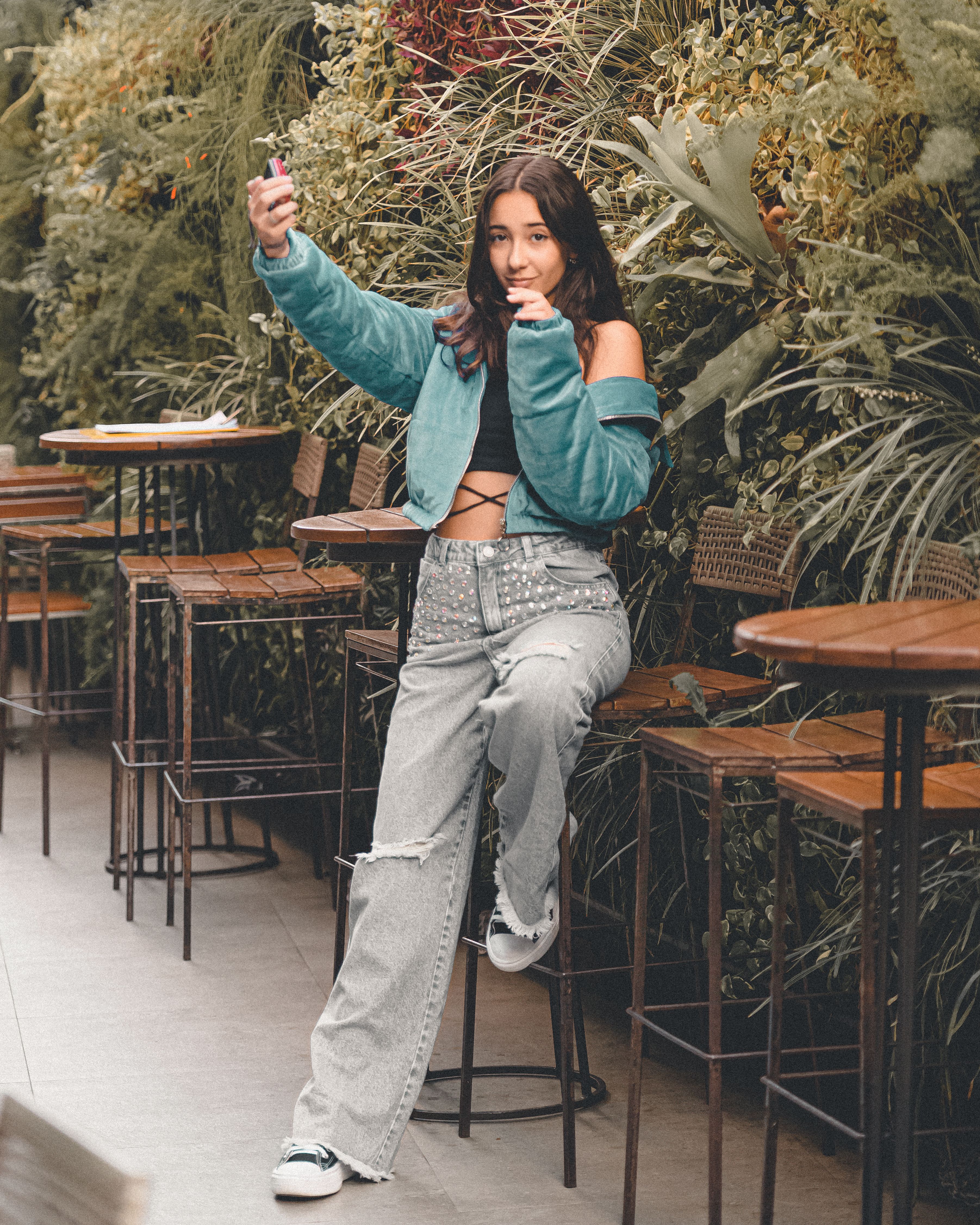 Woman in Jacket Posing near Chairs and Tables · Free Stock Photo