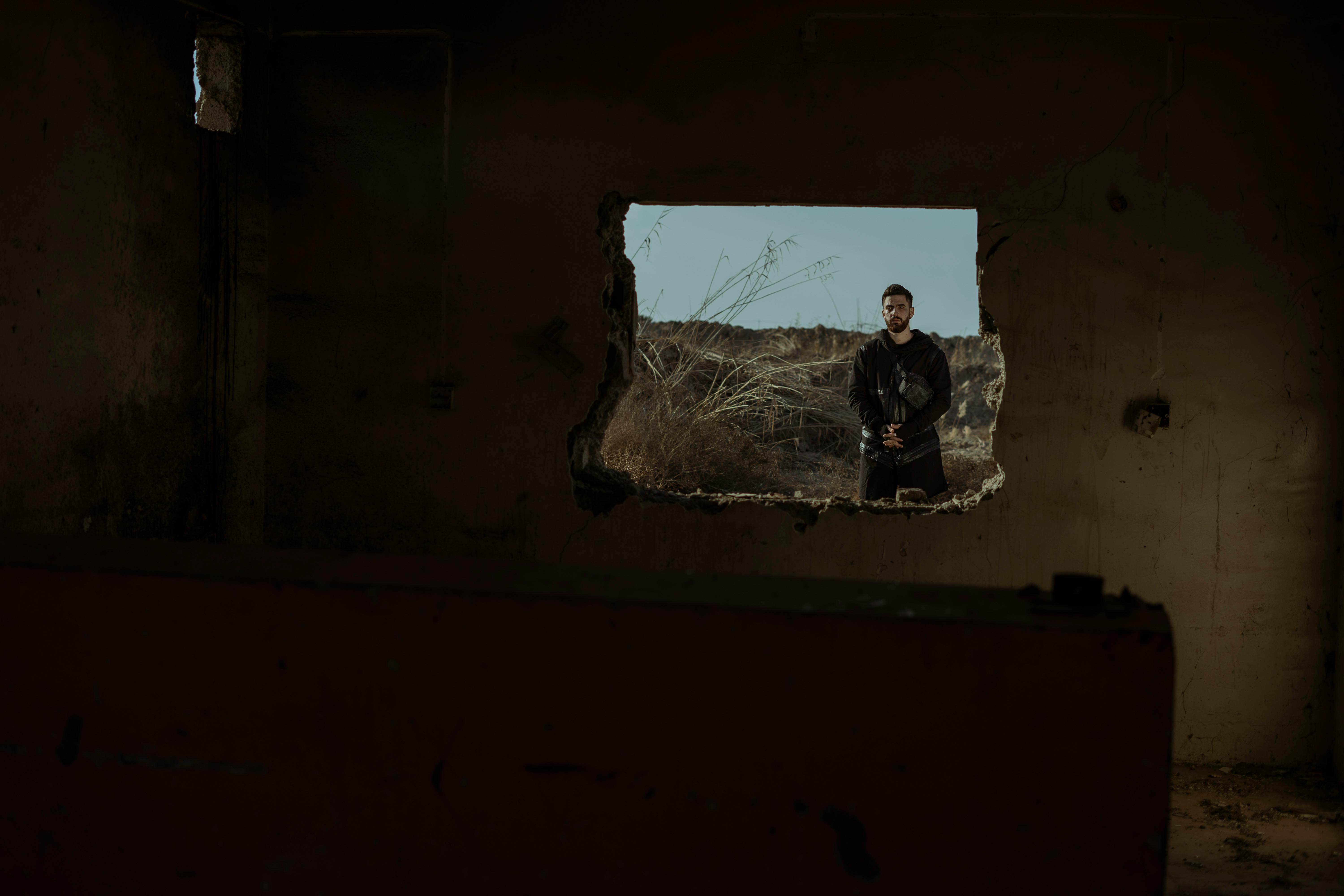 Man Seen through the Window of a Ruined Building · Free Stock Photo