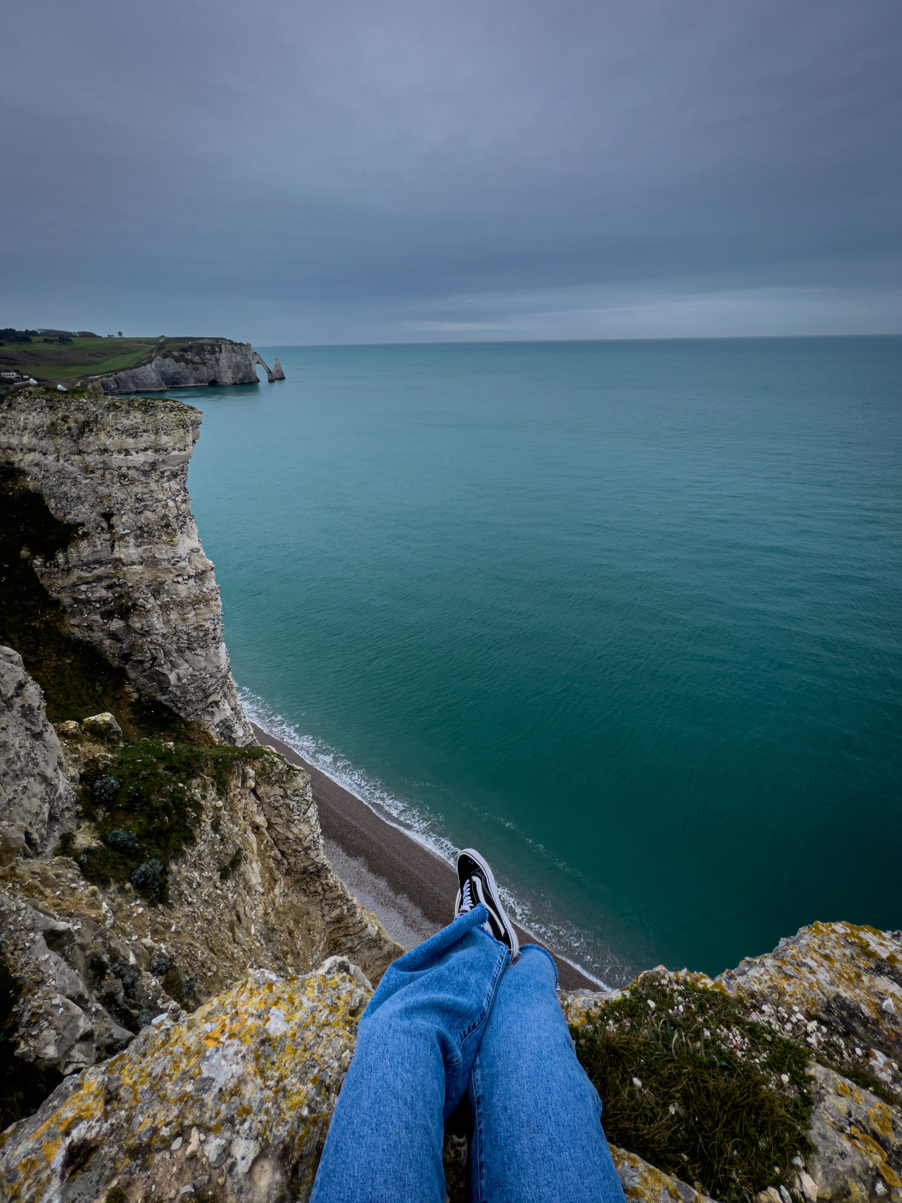 Legs of Person Sitting on Cliff on Sea Shore · Free Stock Photo