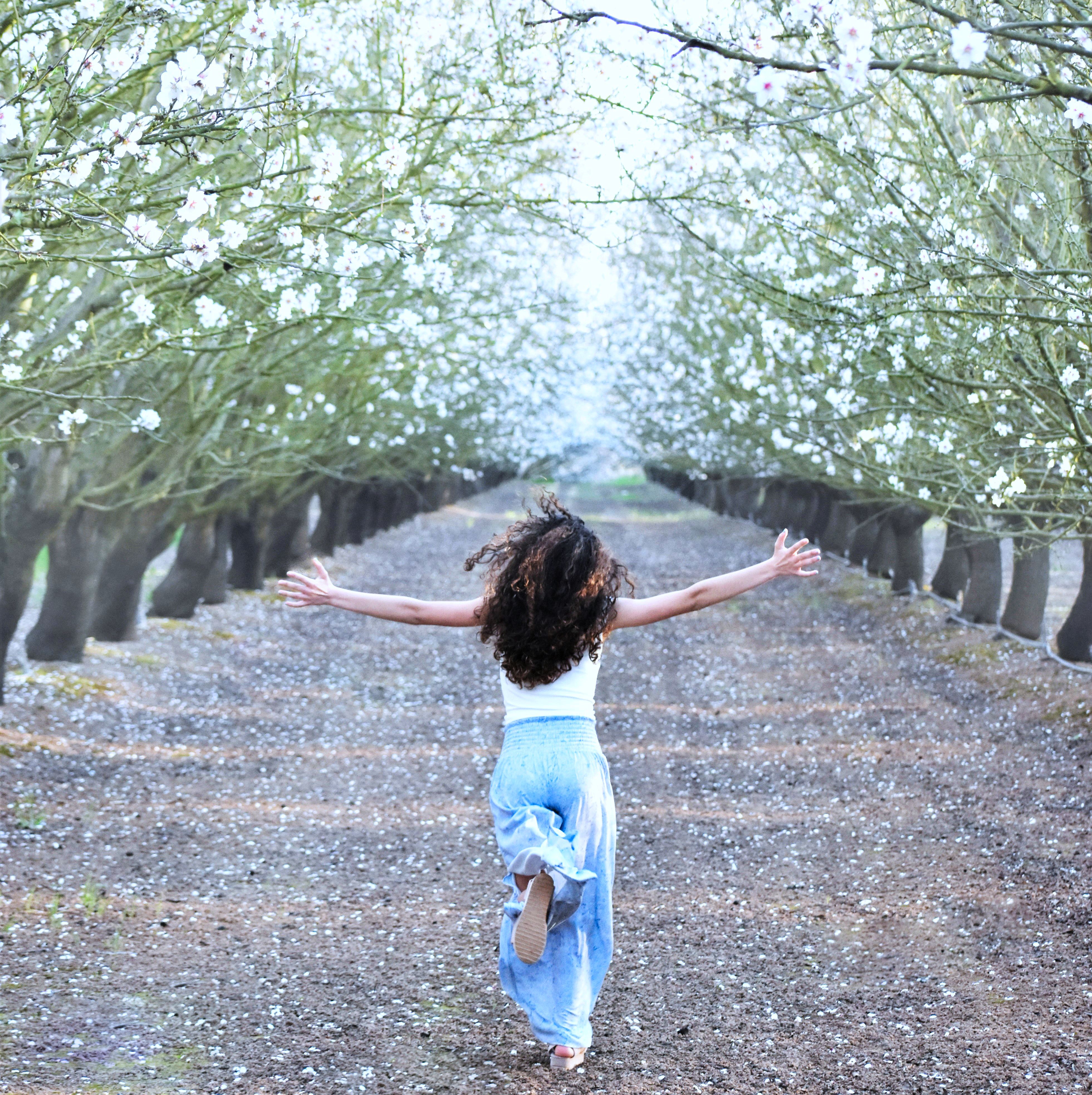 Woman Running through Alley Surrounded by Blooming Trees · Free Stock Photo