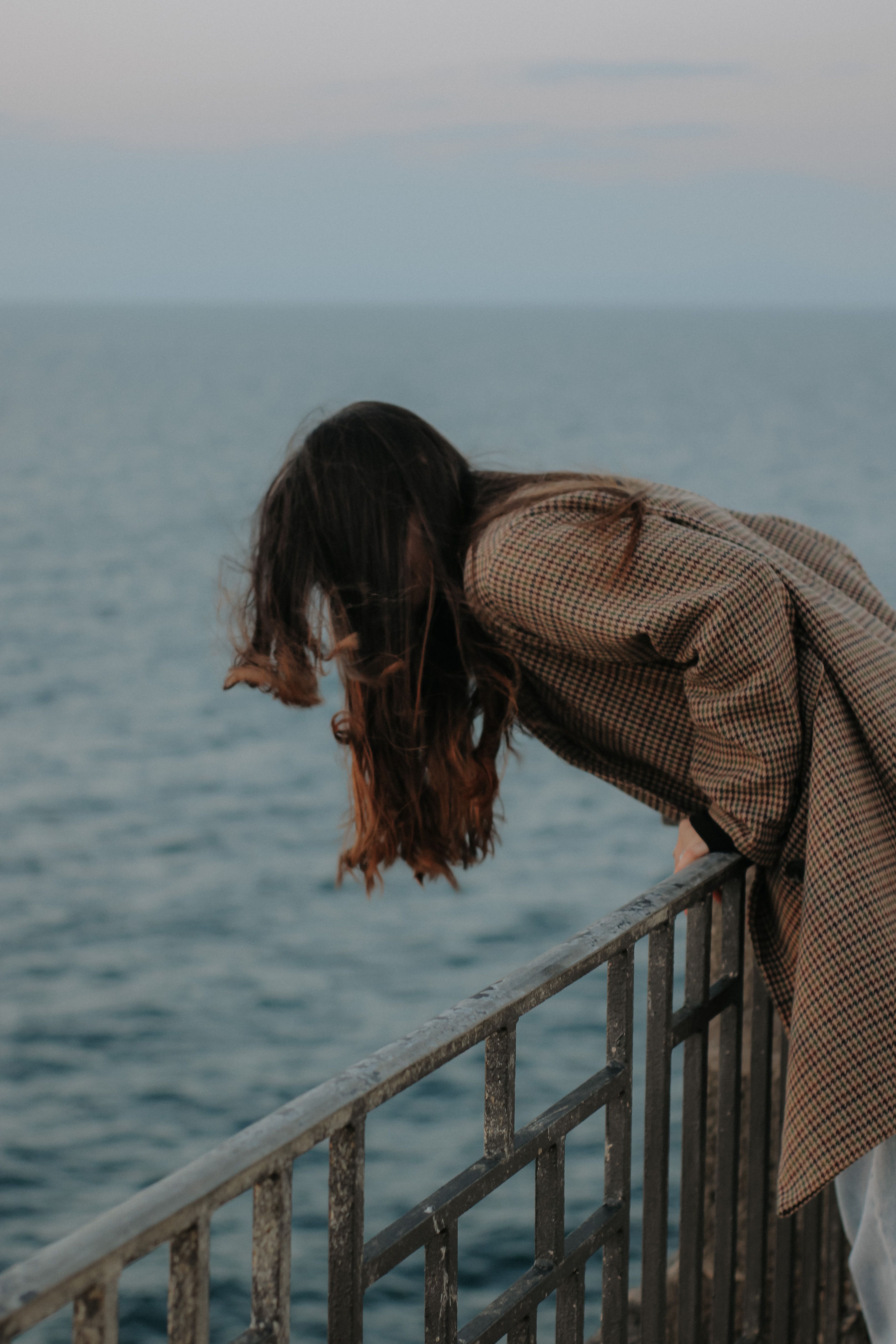Woman Looking Down over Railing on Sea Shore · Free Stock Photo
