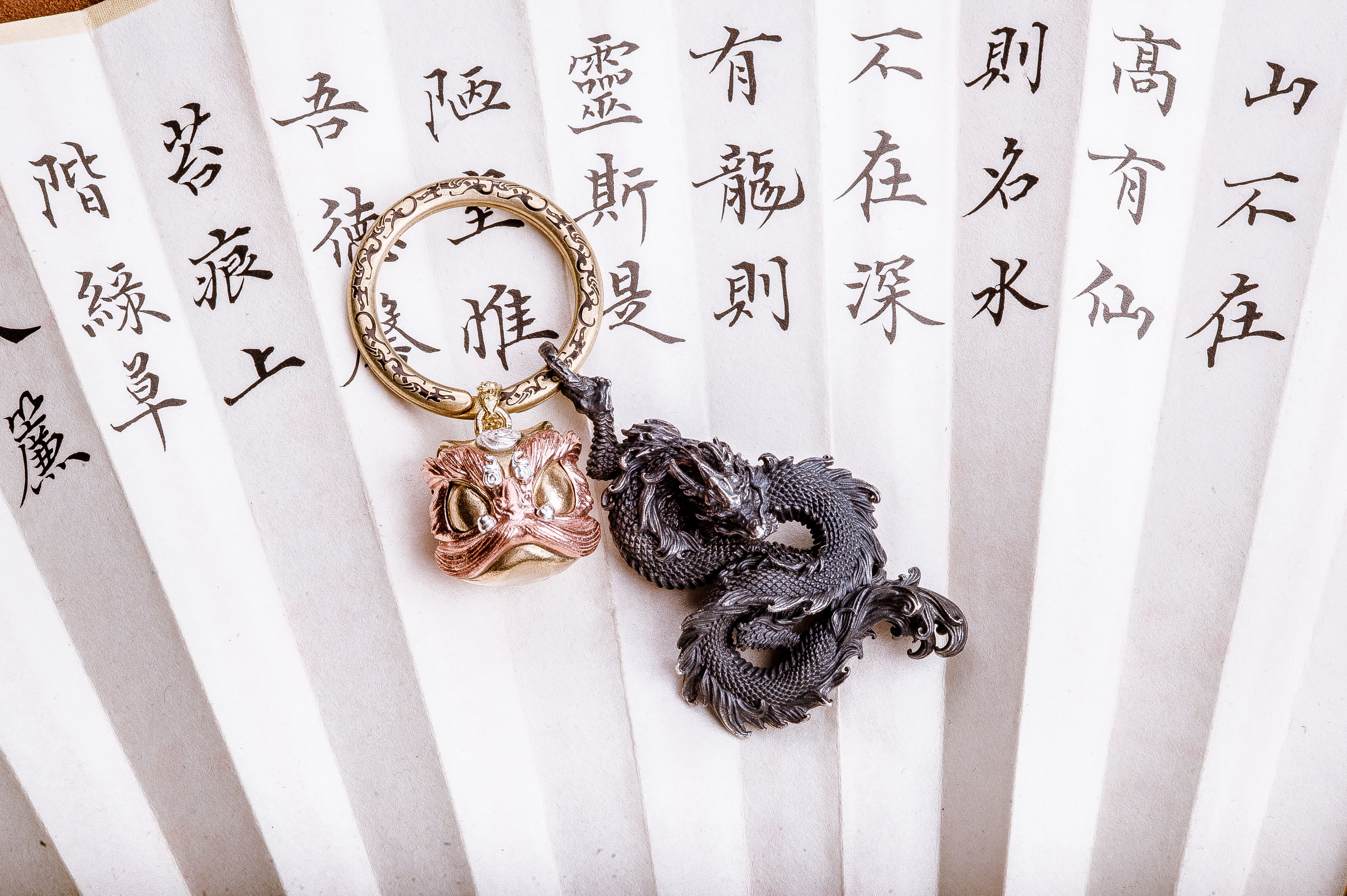 Chinese Dragon Keychain Lying on a White Folding Fan · Free Stock Photo