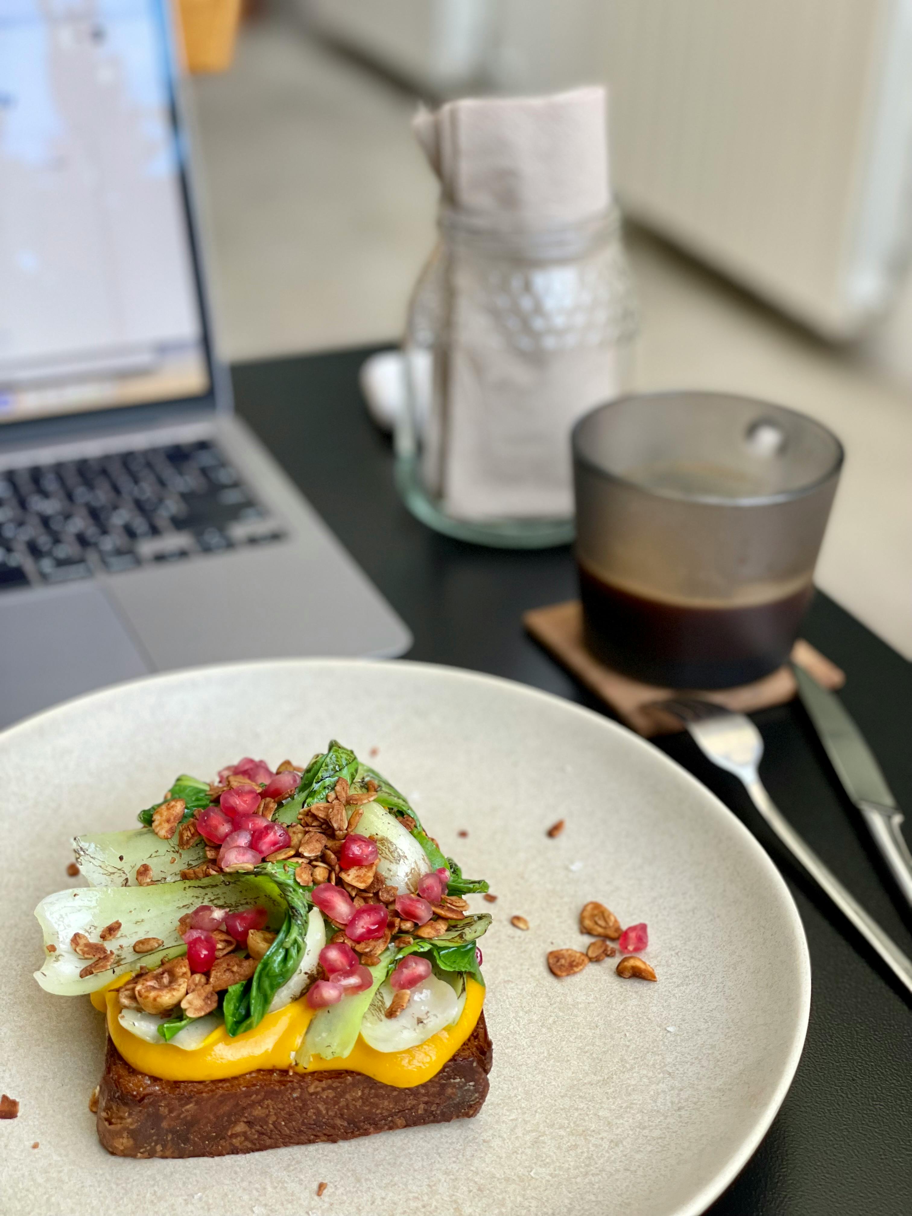 A Toast with Lettuce and Pomegranate and a Cup of Coffee on the Desk ...