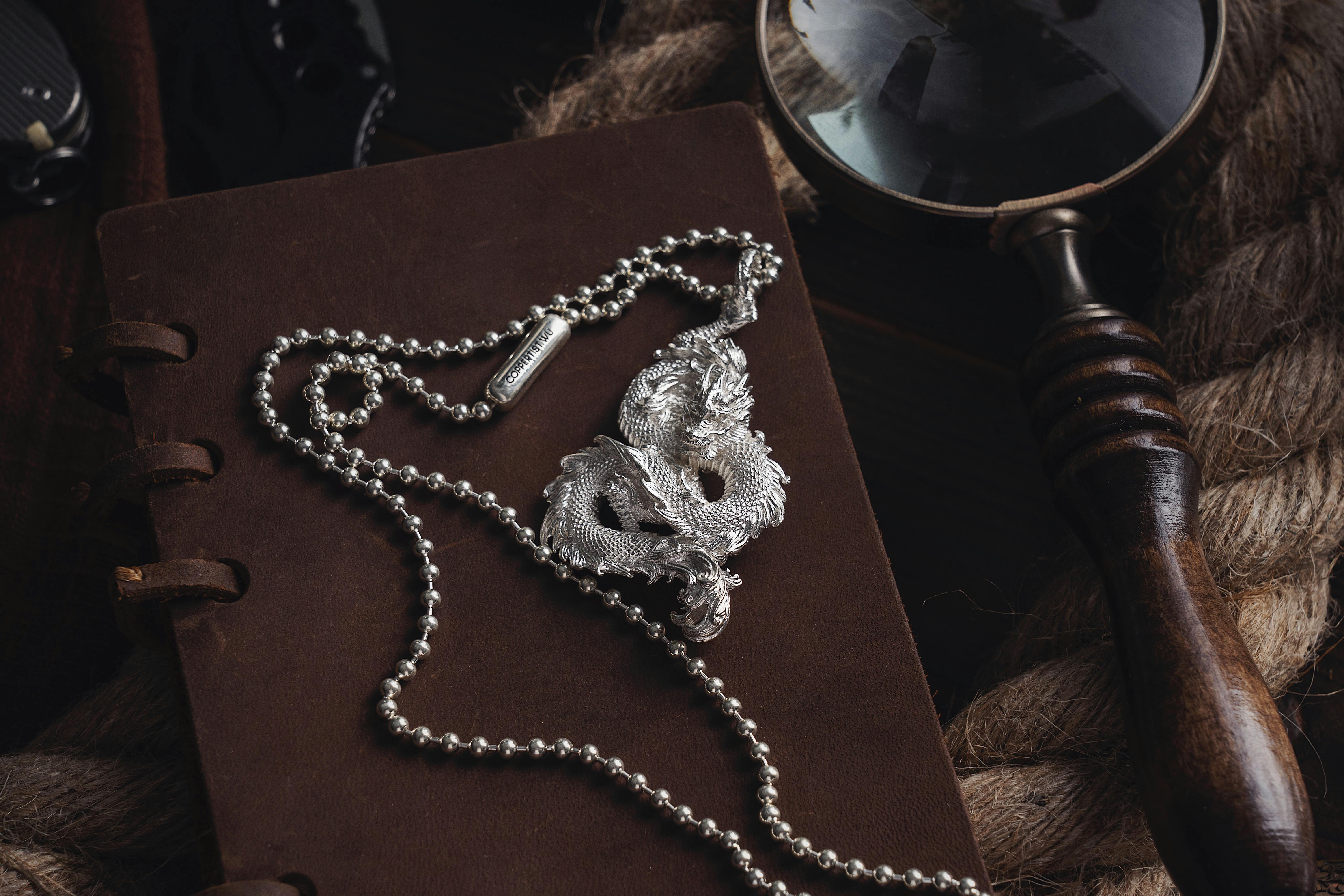 Dragon Necklace Displayed on Notebook · Free Stock Photo