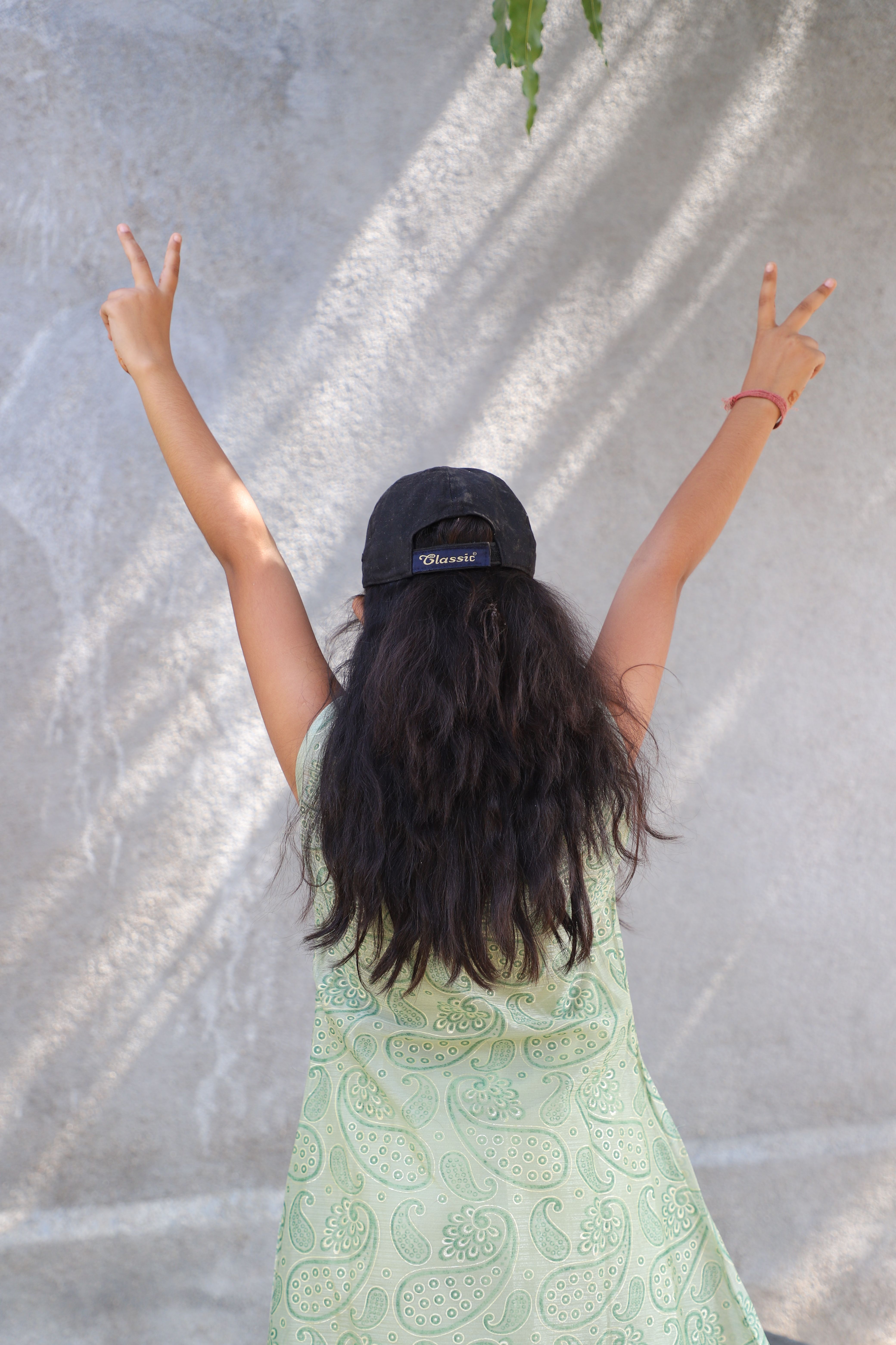 Back View of a Young Brunette Holding Her Arms Raised and Showing Peace ...