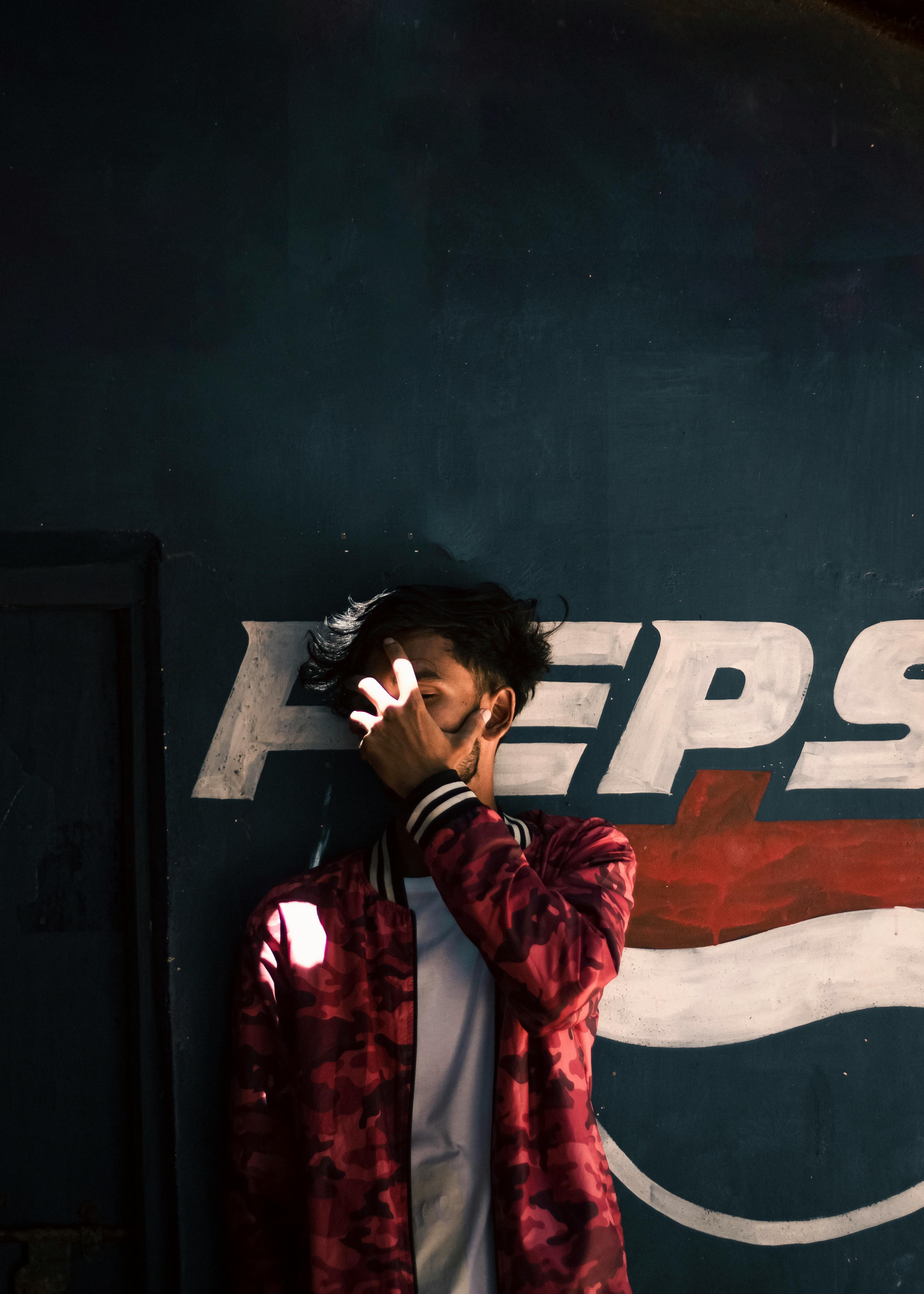 Man Posing by Pepsi Logo on Wall · Free Stock Photo