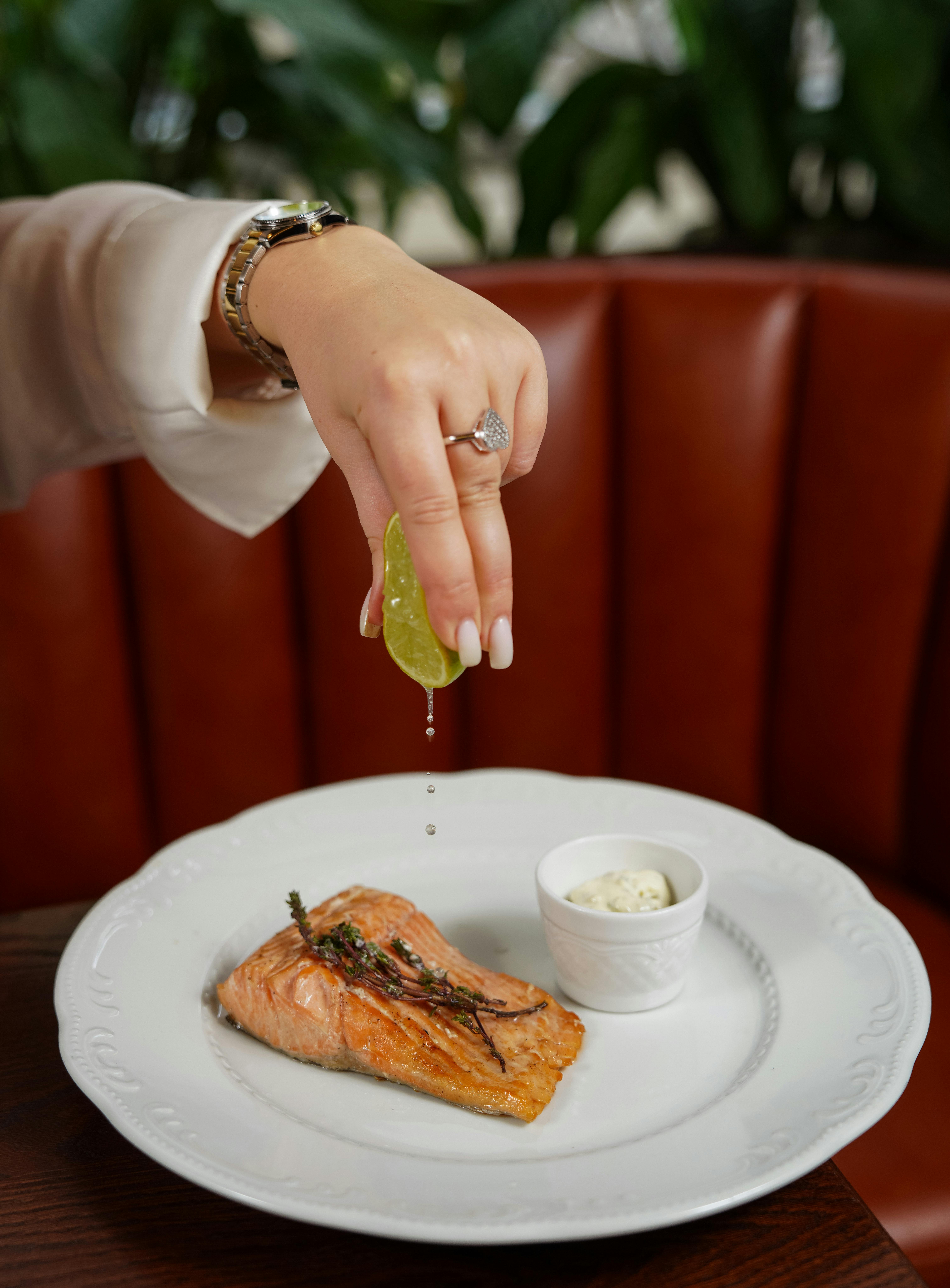Woman Hand Squeezing Lemon over Fish on Plate · Free Stock Photo