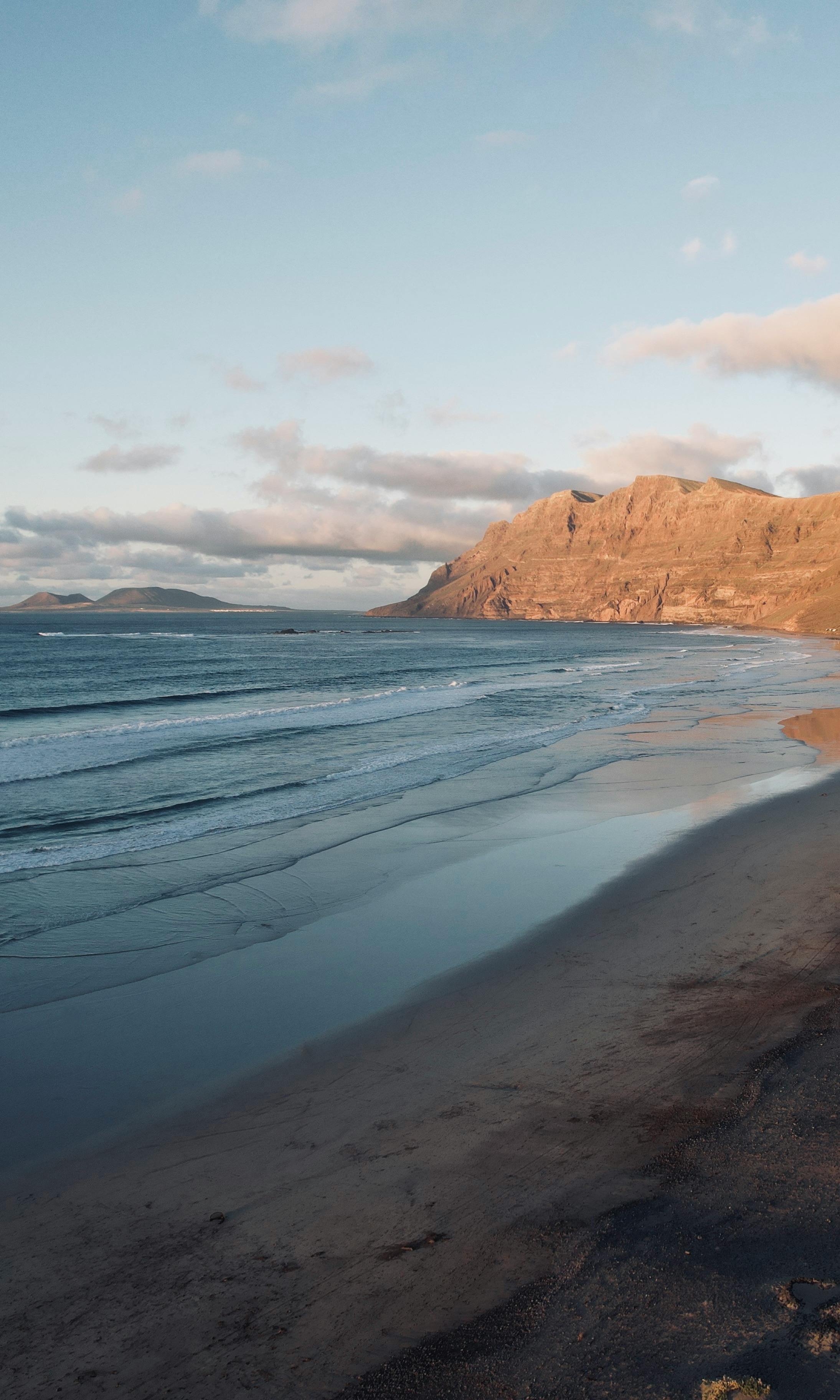 Hill on Sea Shore behind Gap in Wave · Free Stock Photo
