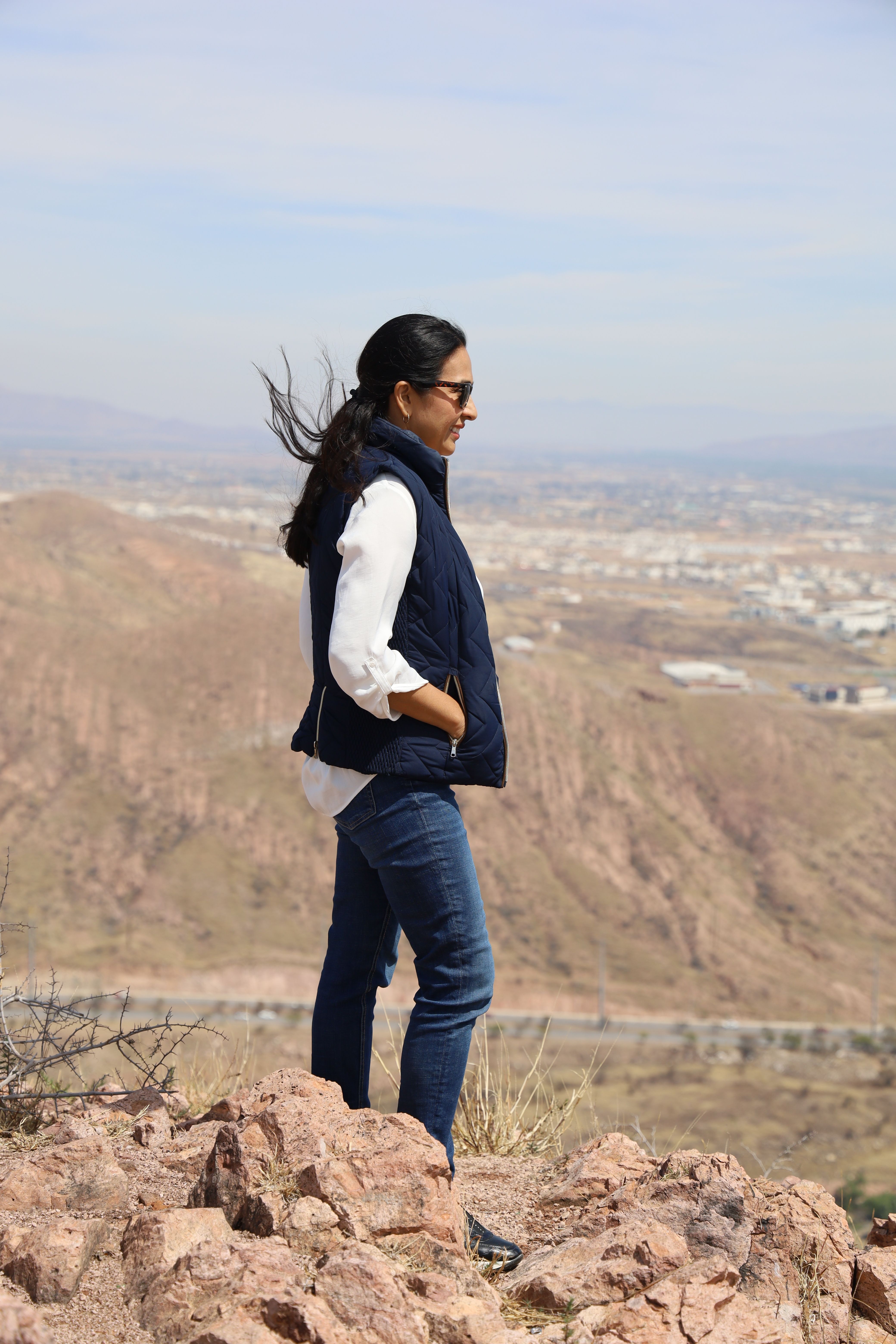 Woman in Vest Standing behind Rocks · Free Stock Photo