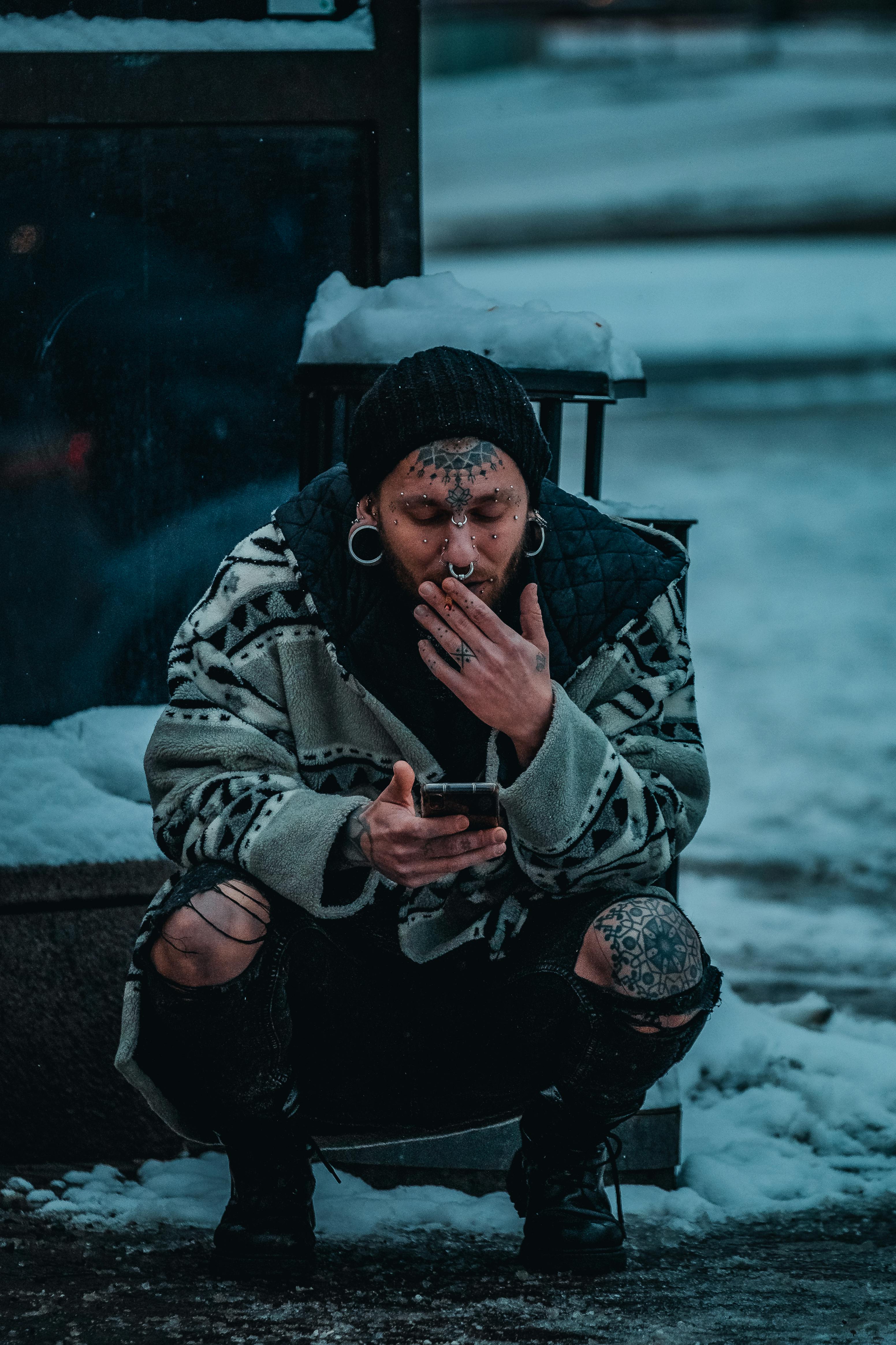 Tattooed Man Smoking Cigarette While Crouching by Trash Bin · Free ...