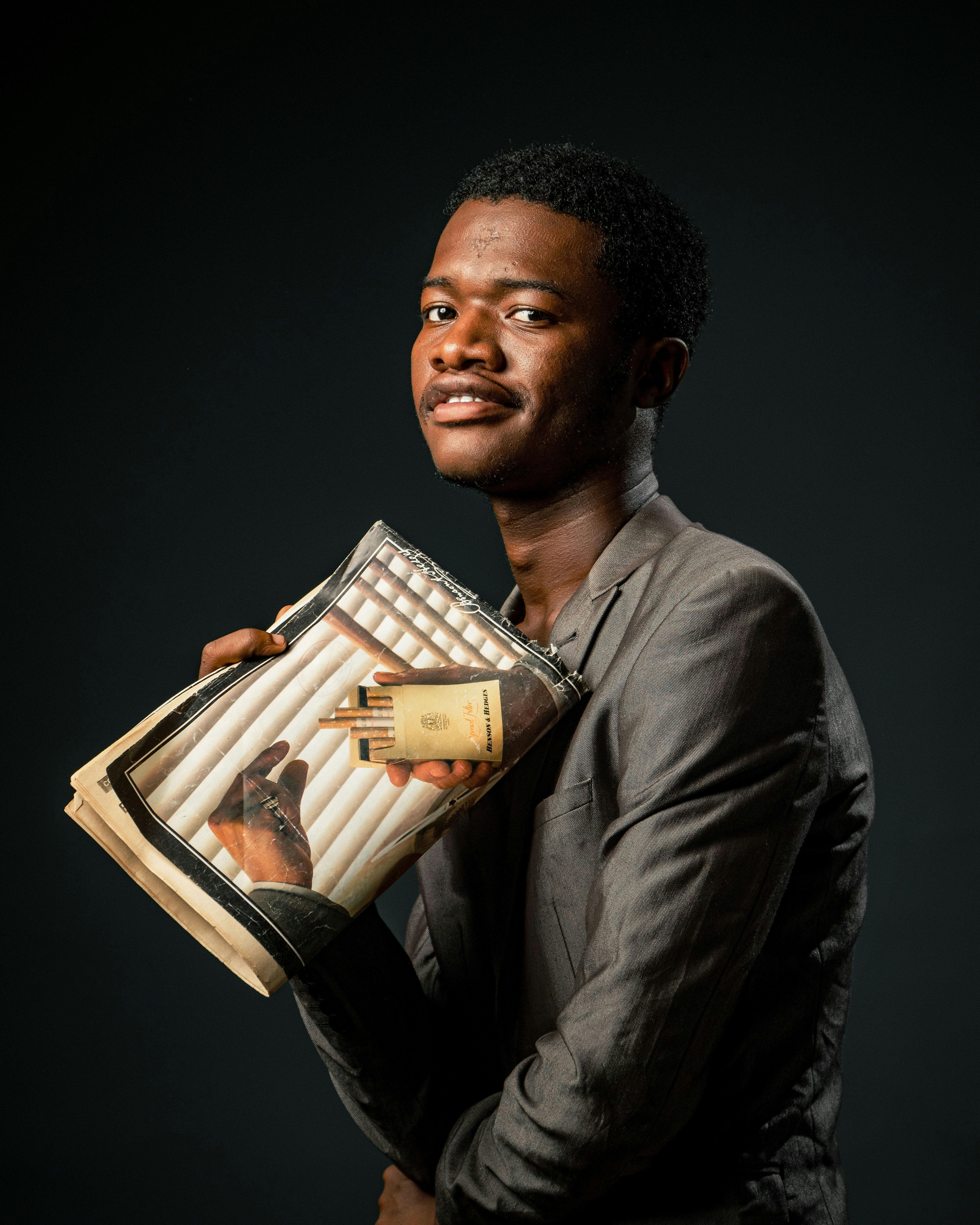 Studio Portrait of a Young Man Holding a Magazine with a Cigarettes ...