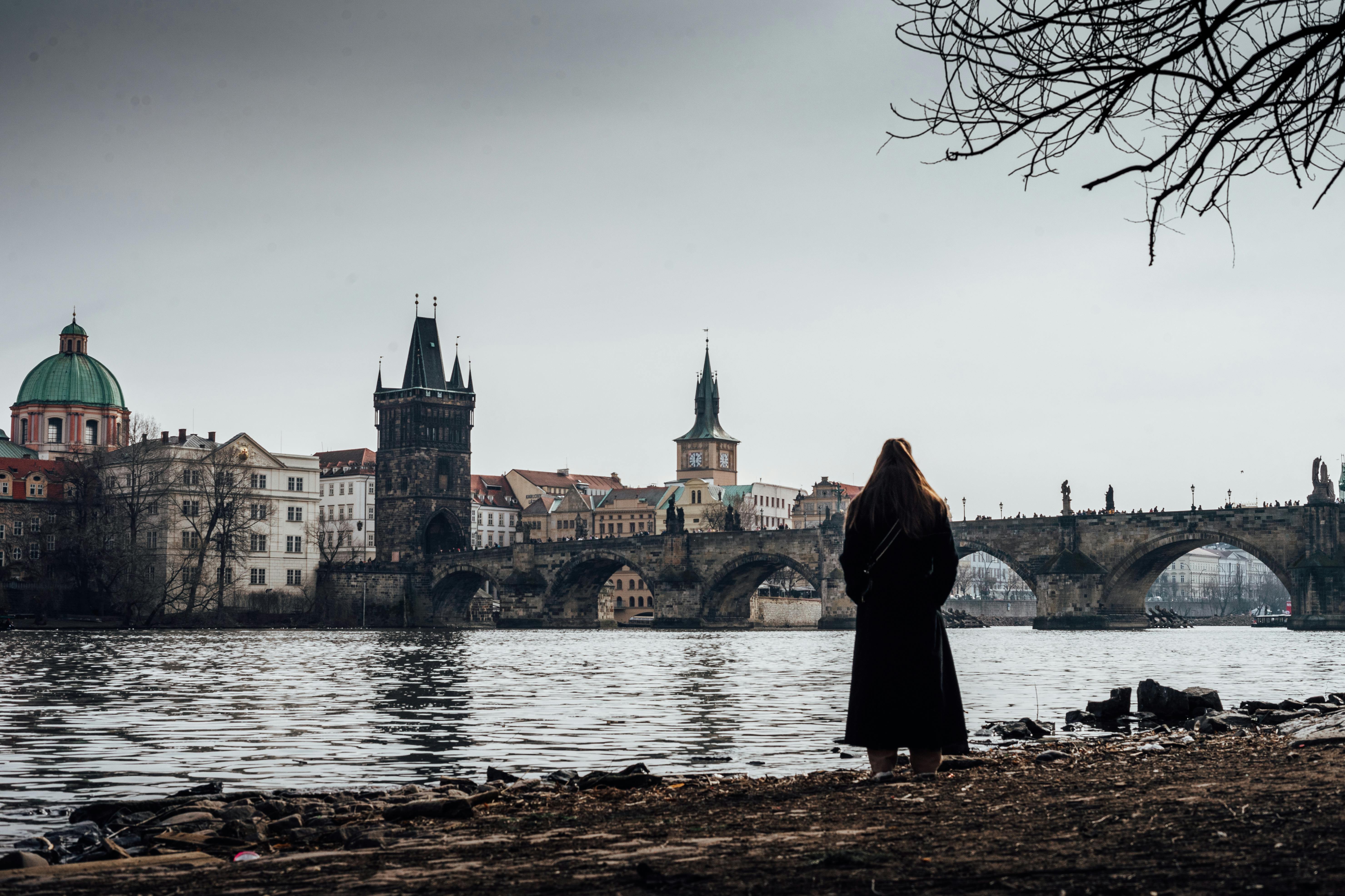 Woman in Coat Looking at Bridge over River in City · Free Stock Photo