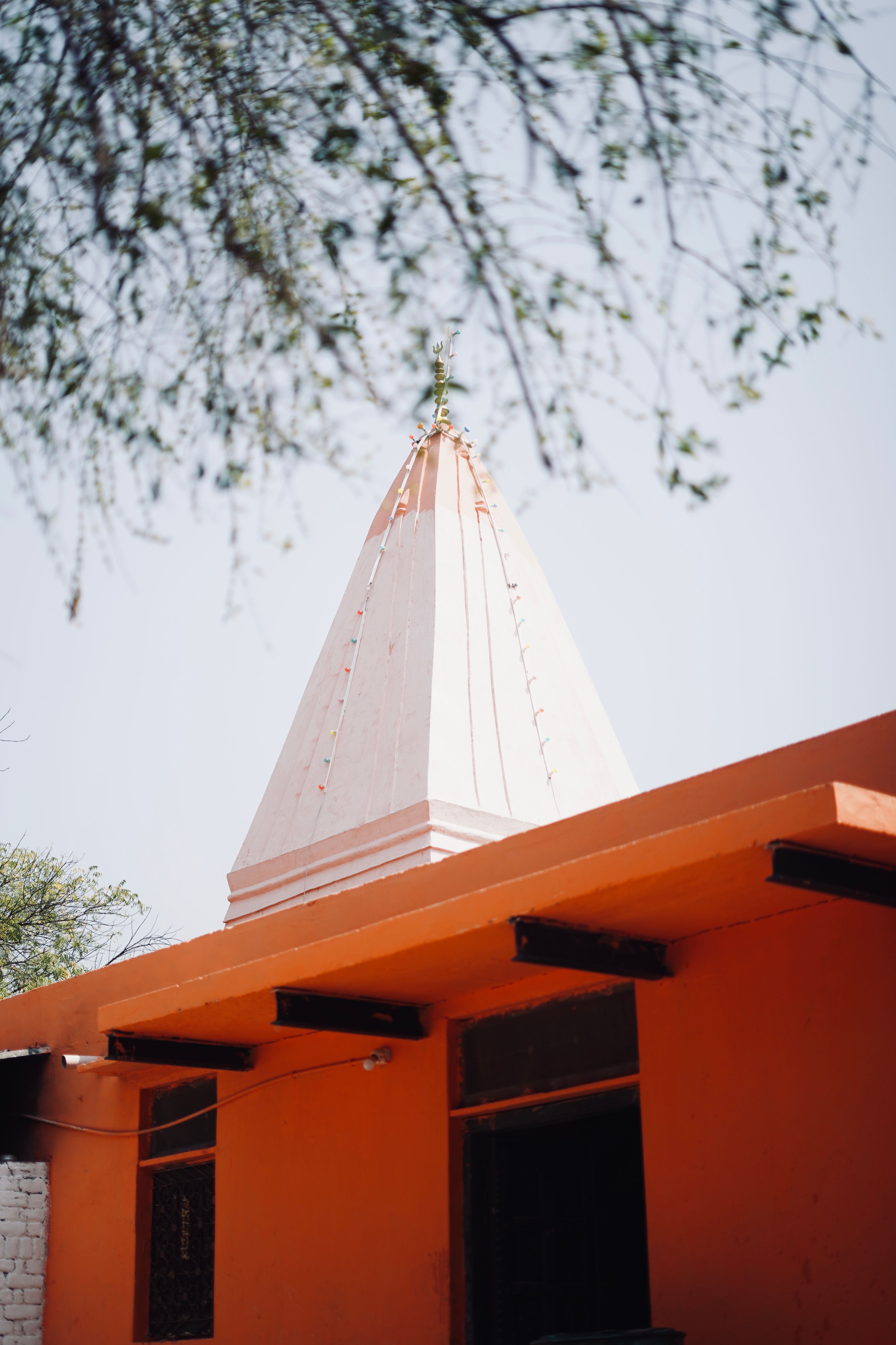 Tower of a Temple behind an Orange Building · Free Stock Photo
