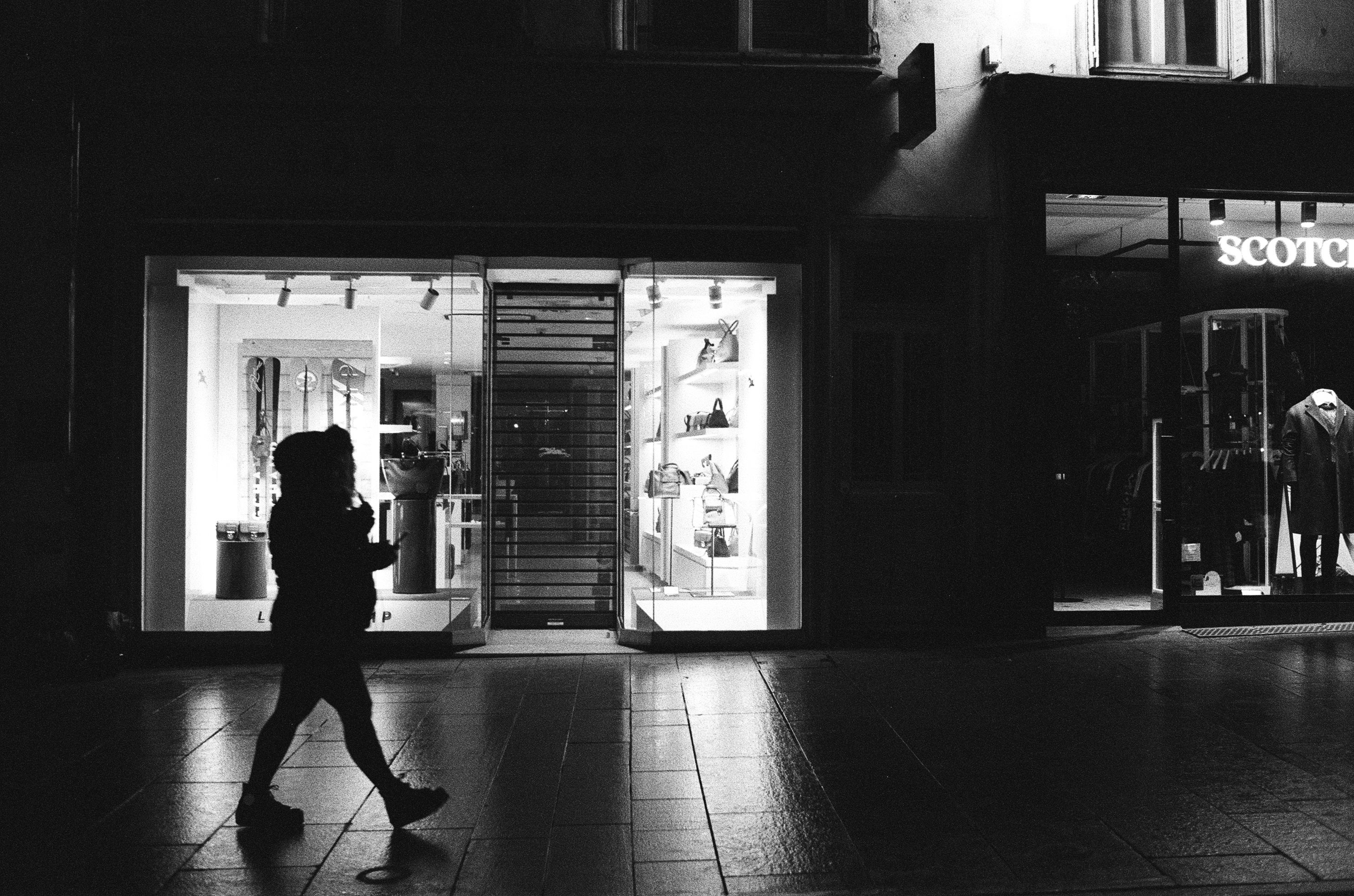 Woman Walking along Stores at Night · Free Stock Photo