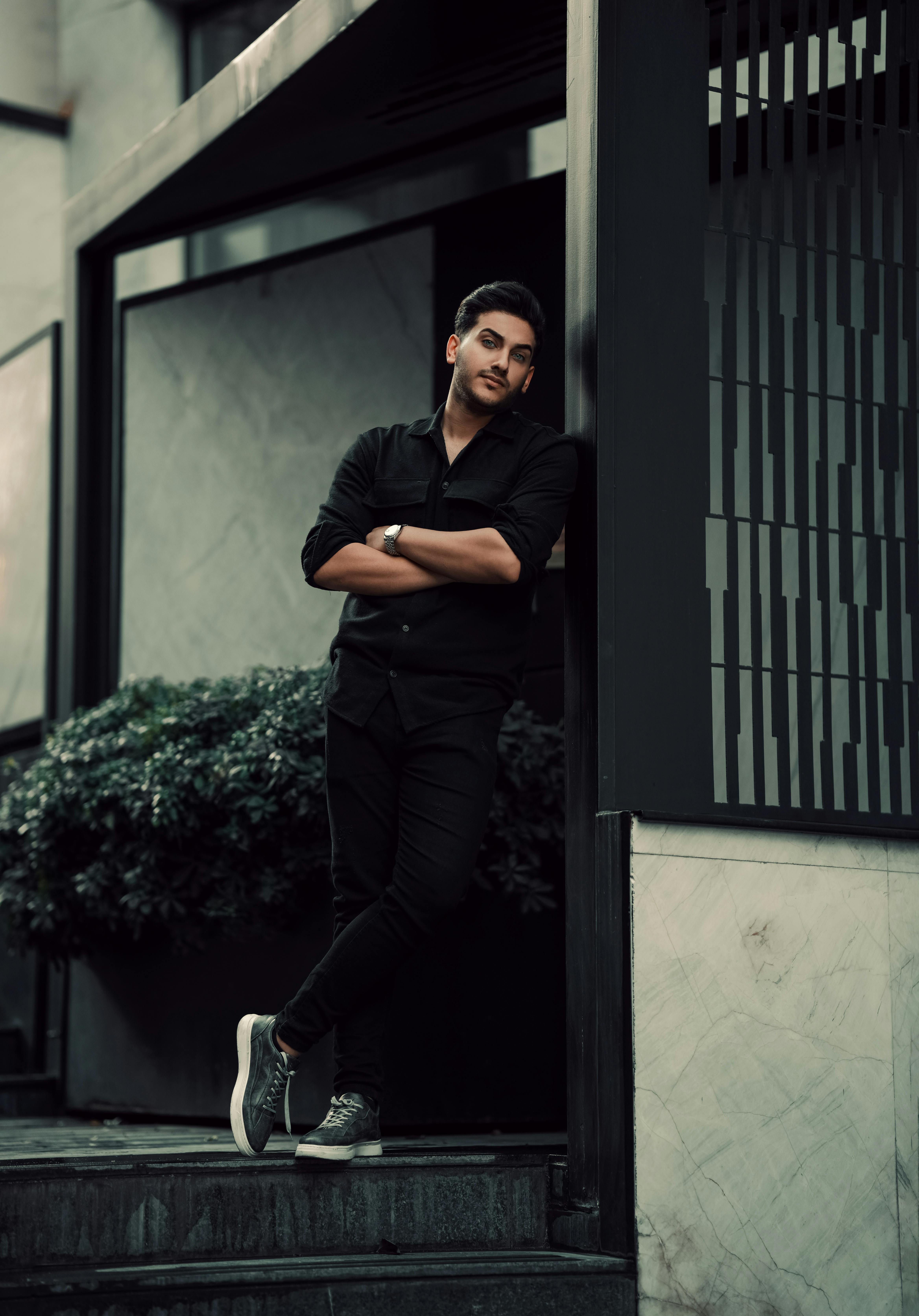 Man Standing and Leaning against a Building Facade · Free Stock Photo