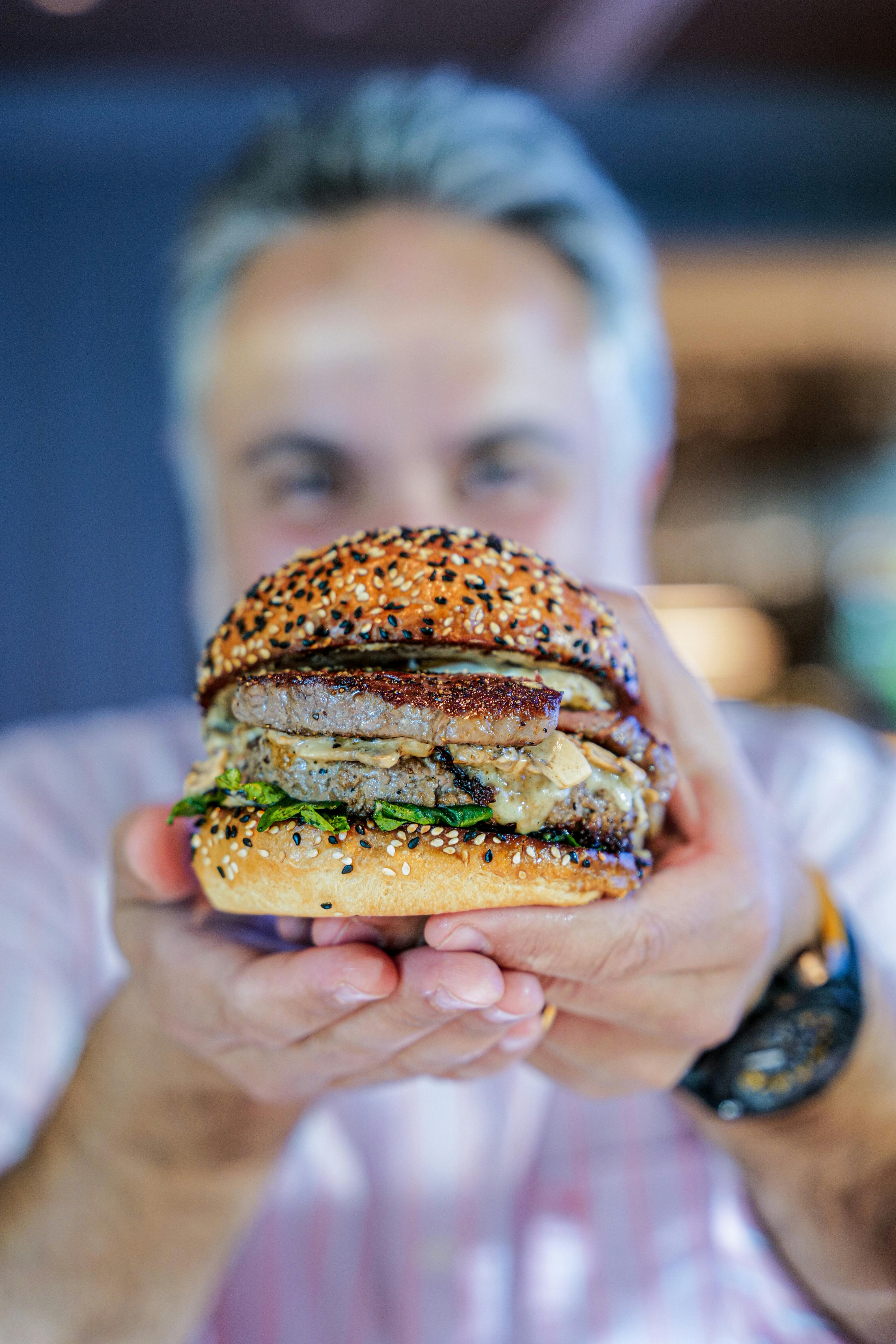 Smiling black man eating burger and taking selfie · Free Stock Photo