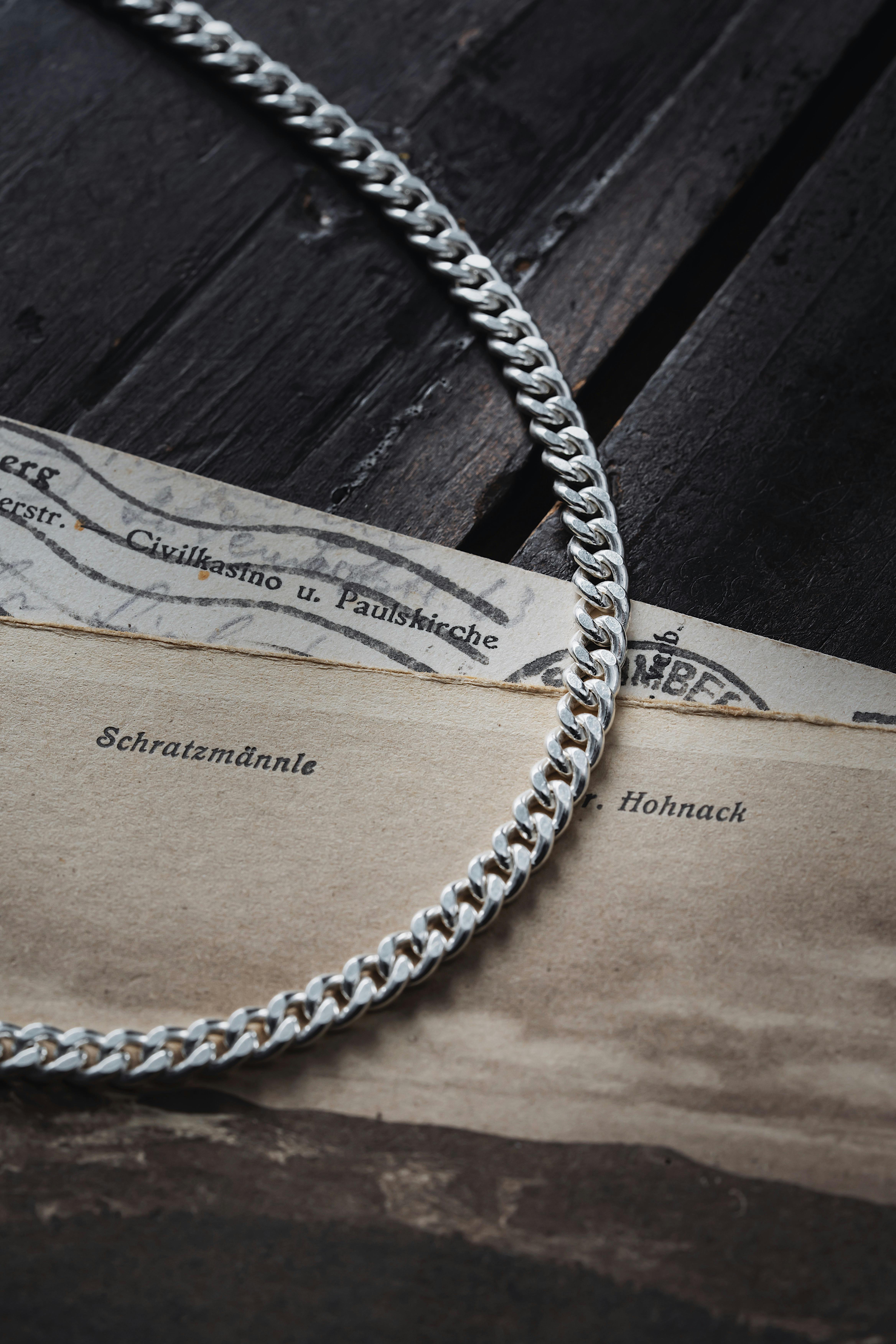 Silver Cuban Link Chain on Old Letters · Free Stock Photo