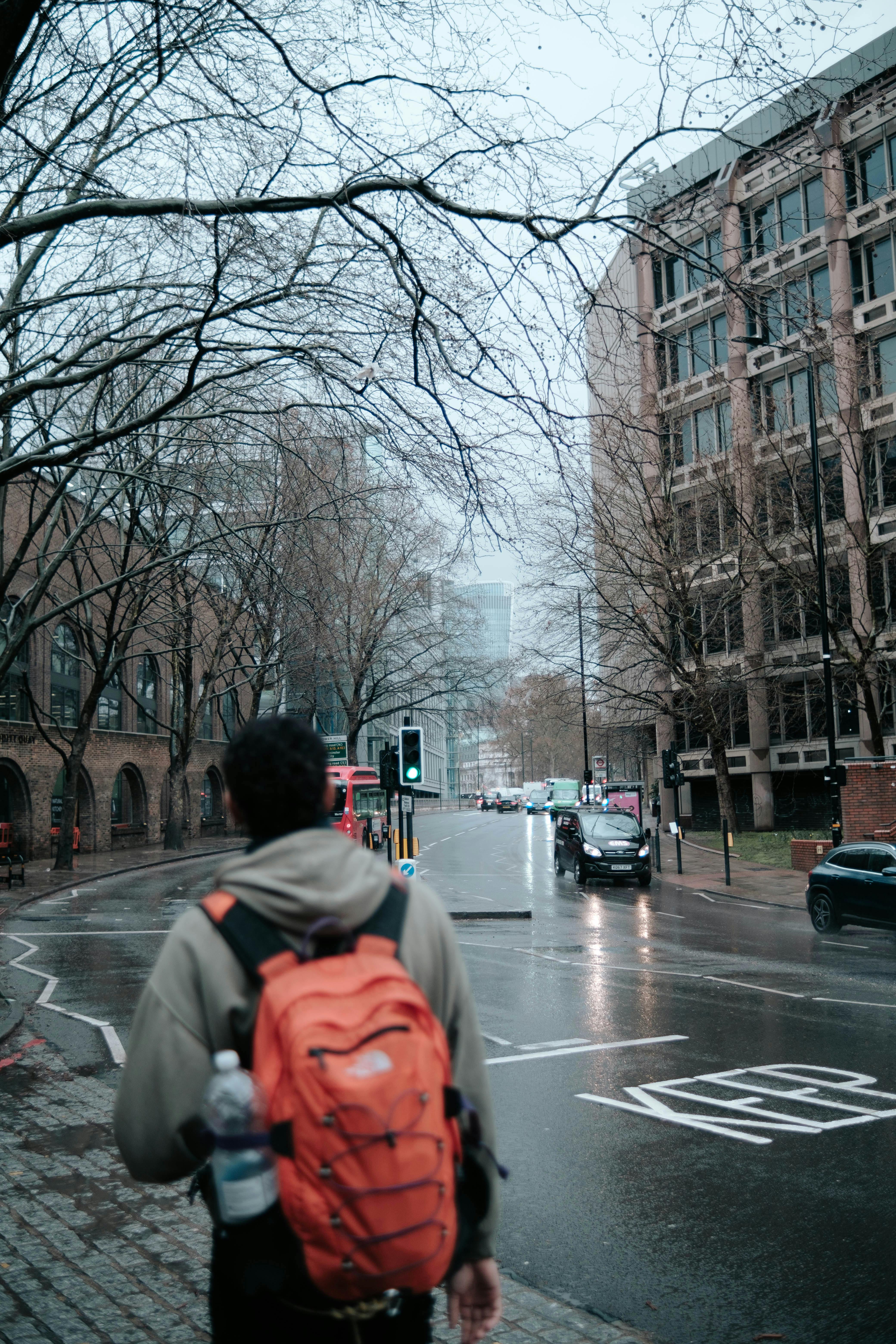 Man with Backpack Walking on City Street in Rain · Free Stock Photo