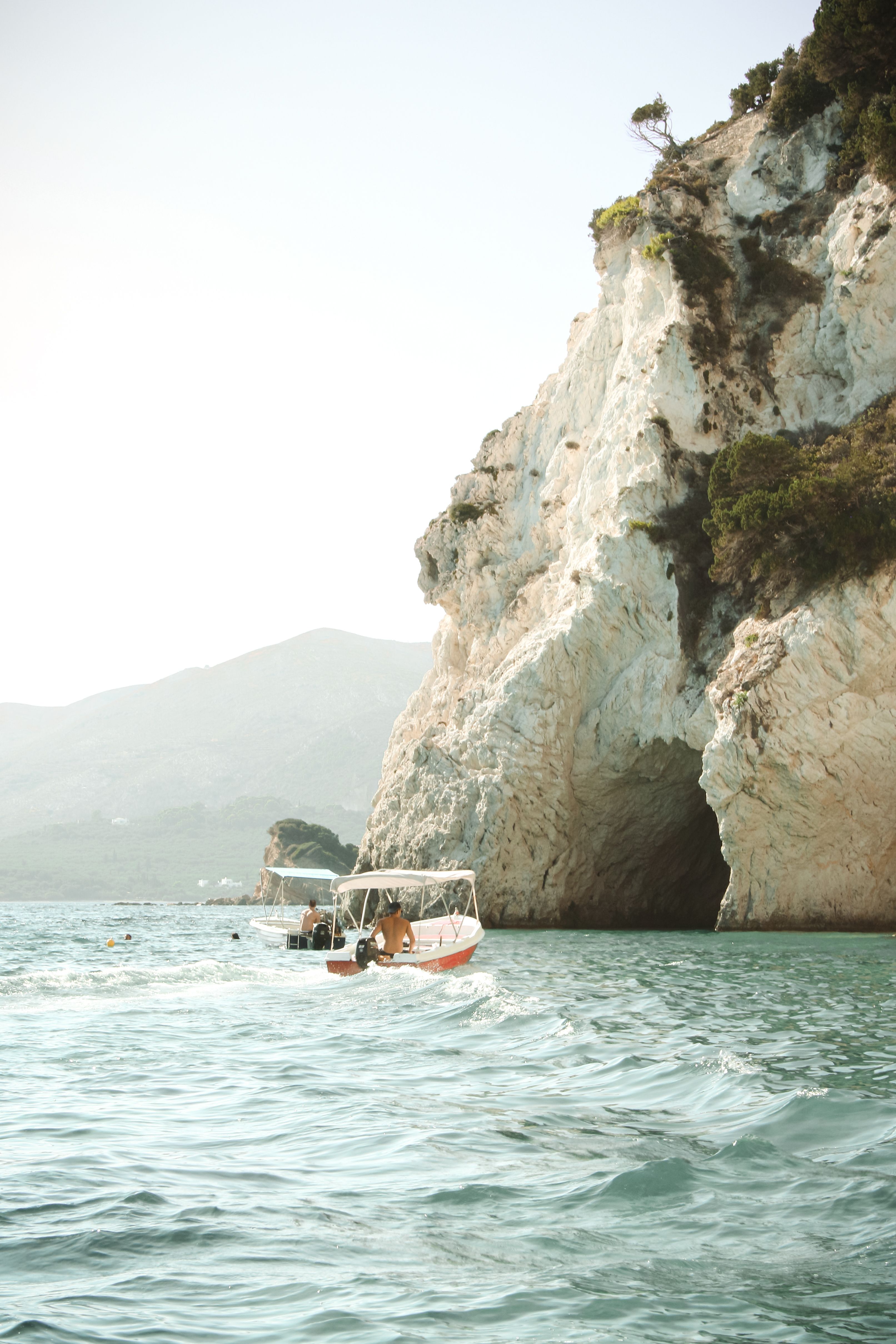 A boat is in the water near a cliff · Free Stock Photo