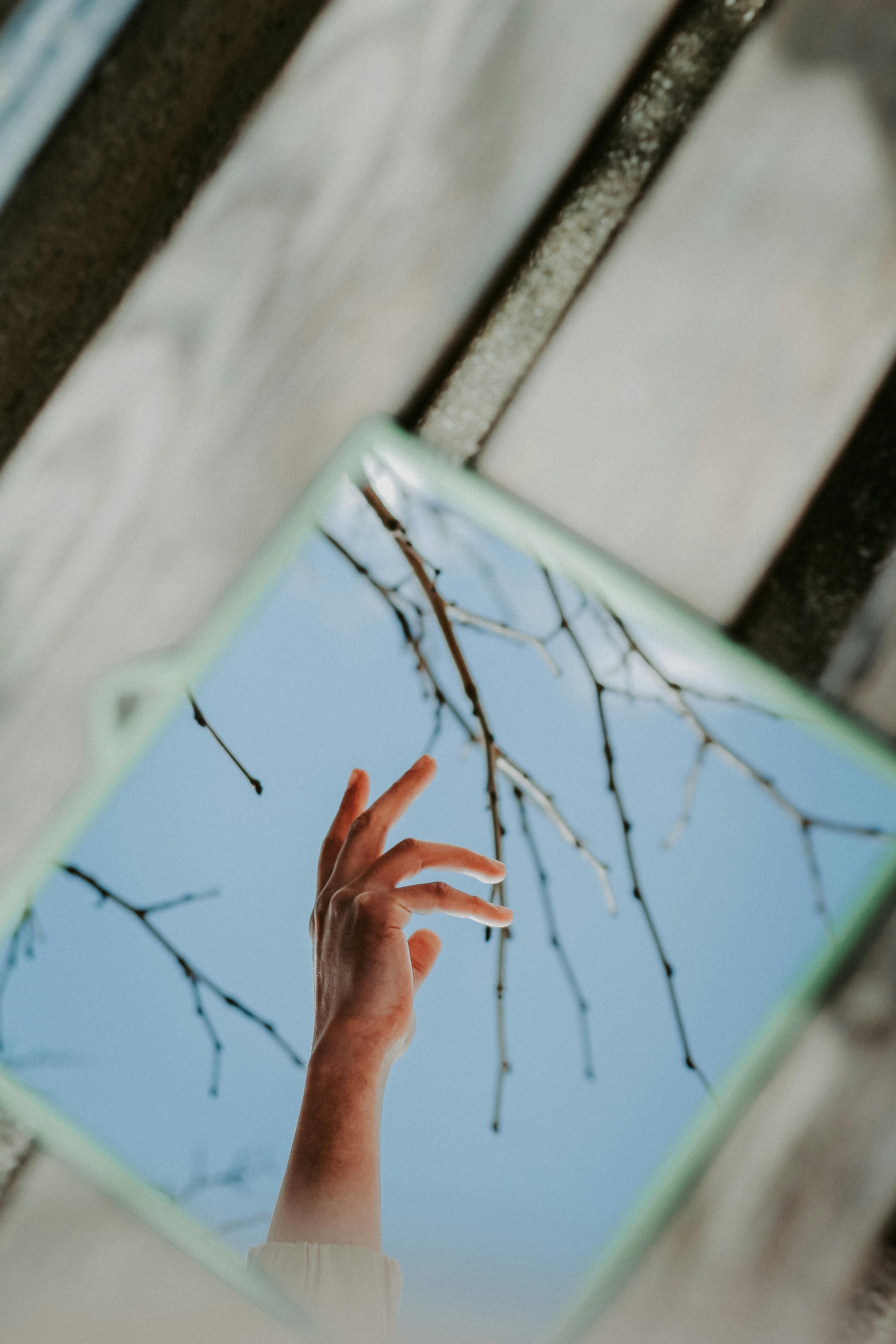 Reflection of Hand against Blue Sky in Mirror Lying on Table · Free ...