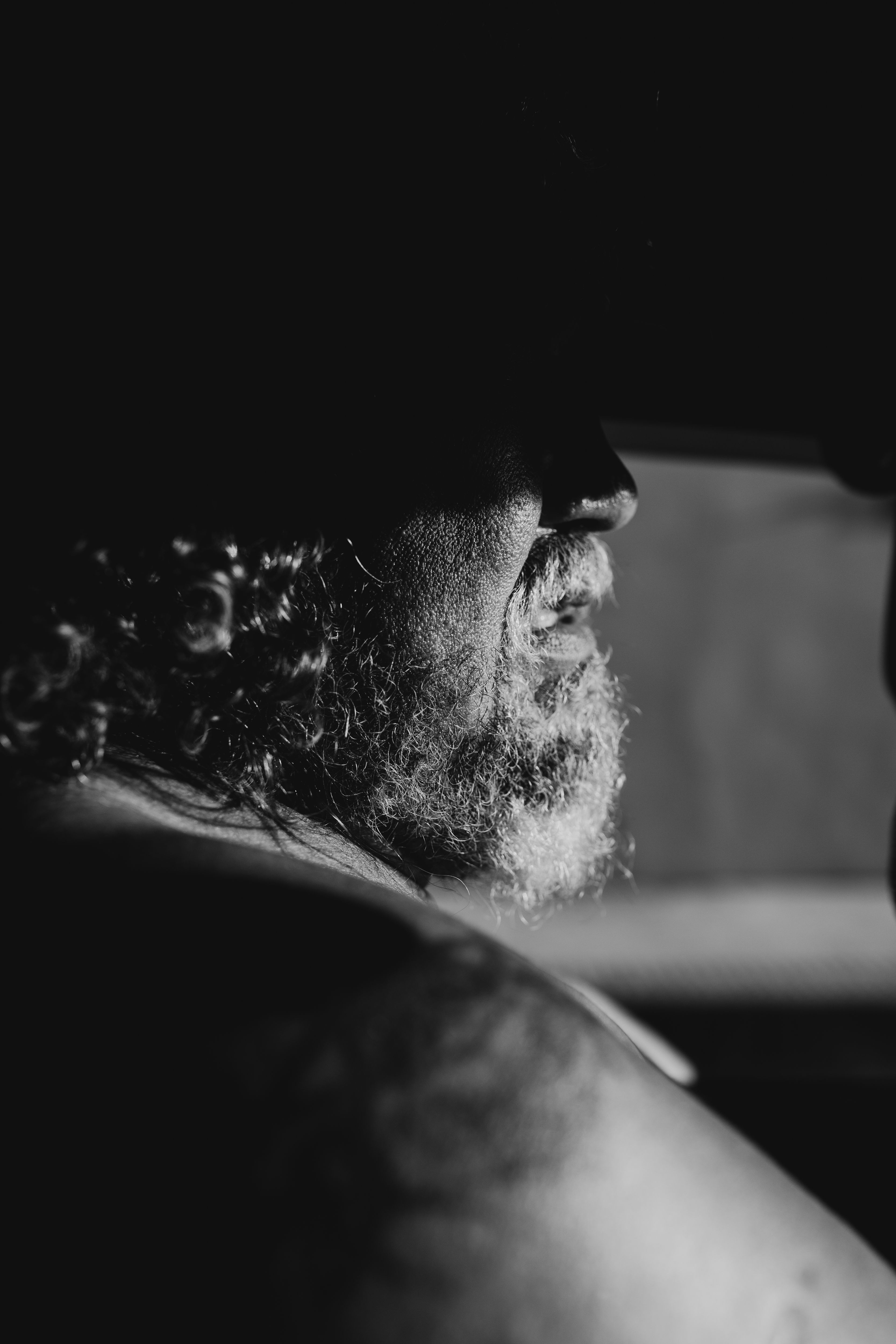 Black and White Photo of Bearded Man Sitting in Shade · Free Stock Photo