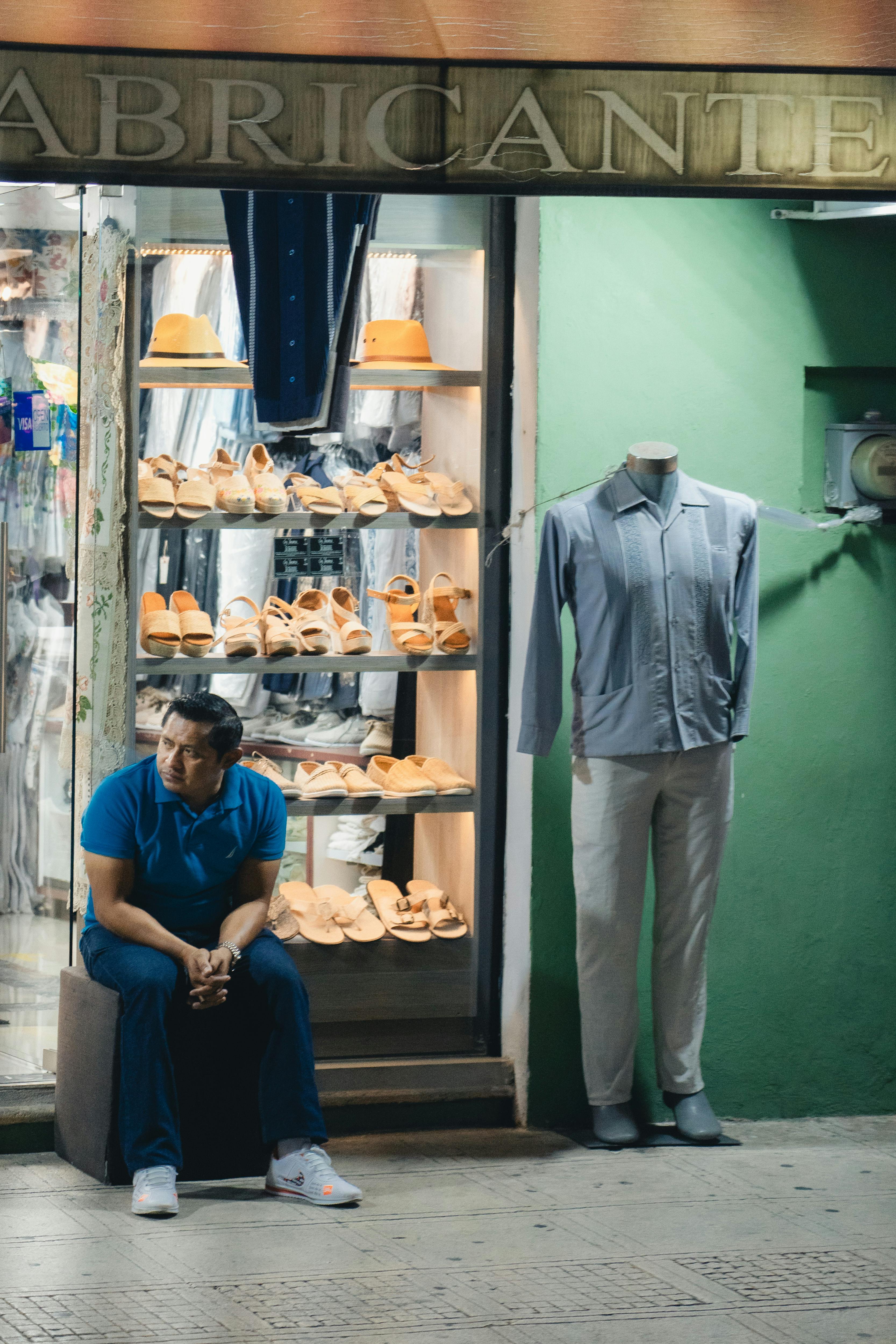 Man Sitting on Stool in front of Shoes Store · Free Stock Photo