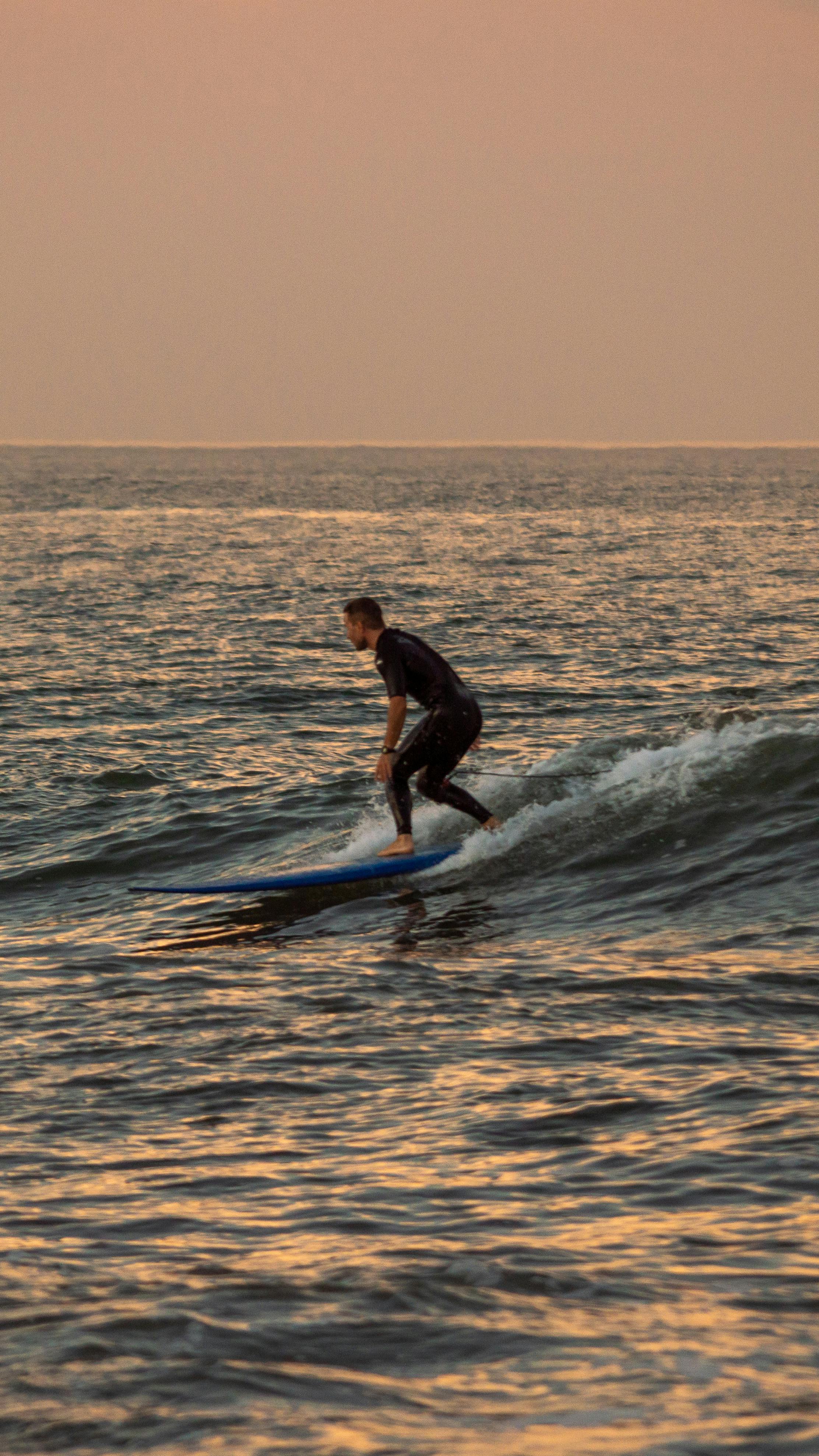 Man Surfing through Waves at Sunset · Free Stock Photo