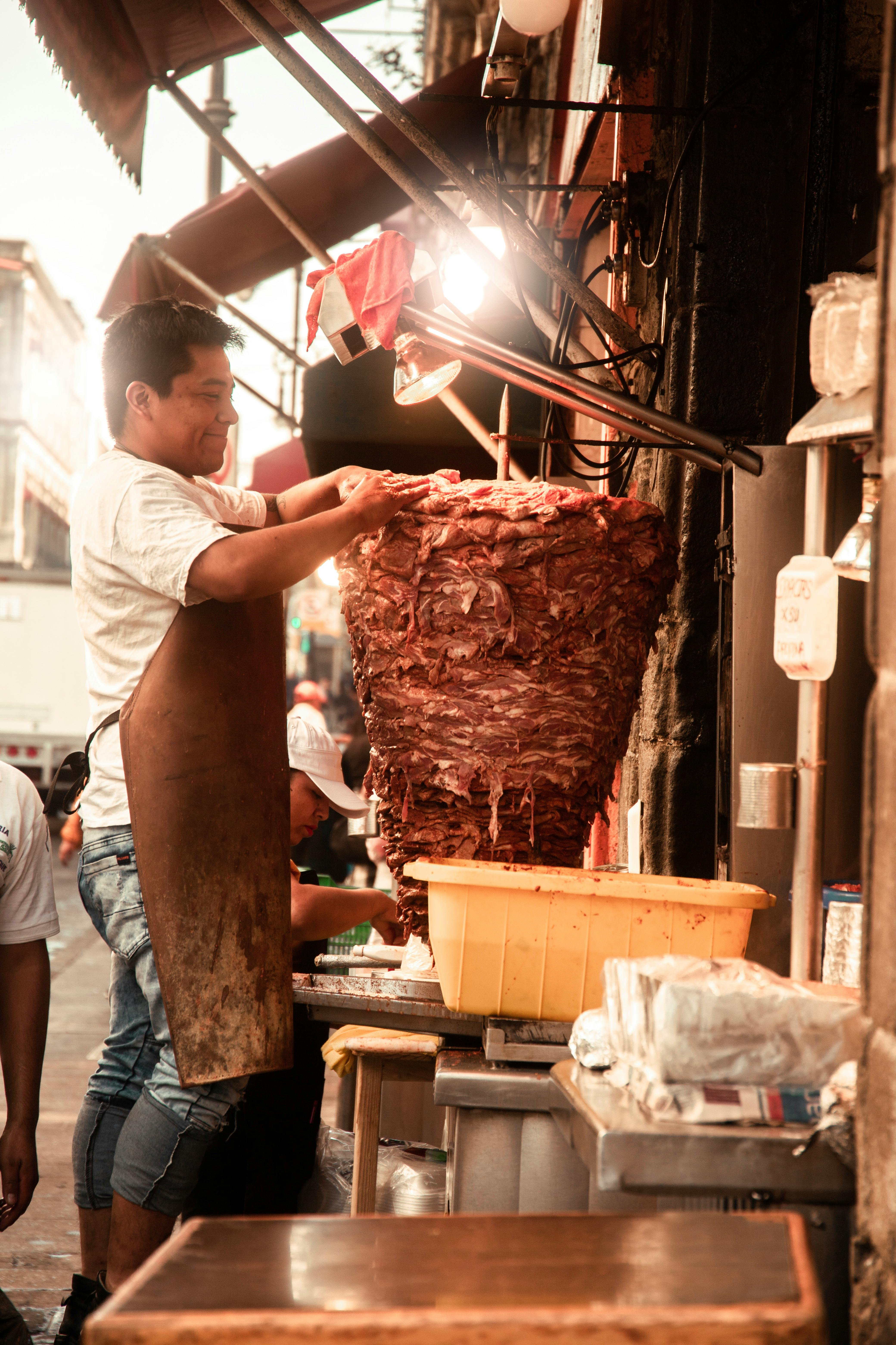 Man in an Apron Putting Meat on a Pole · Free Stock Photo