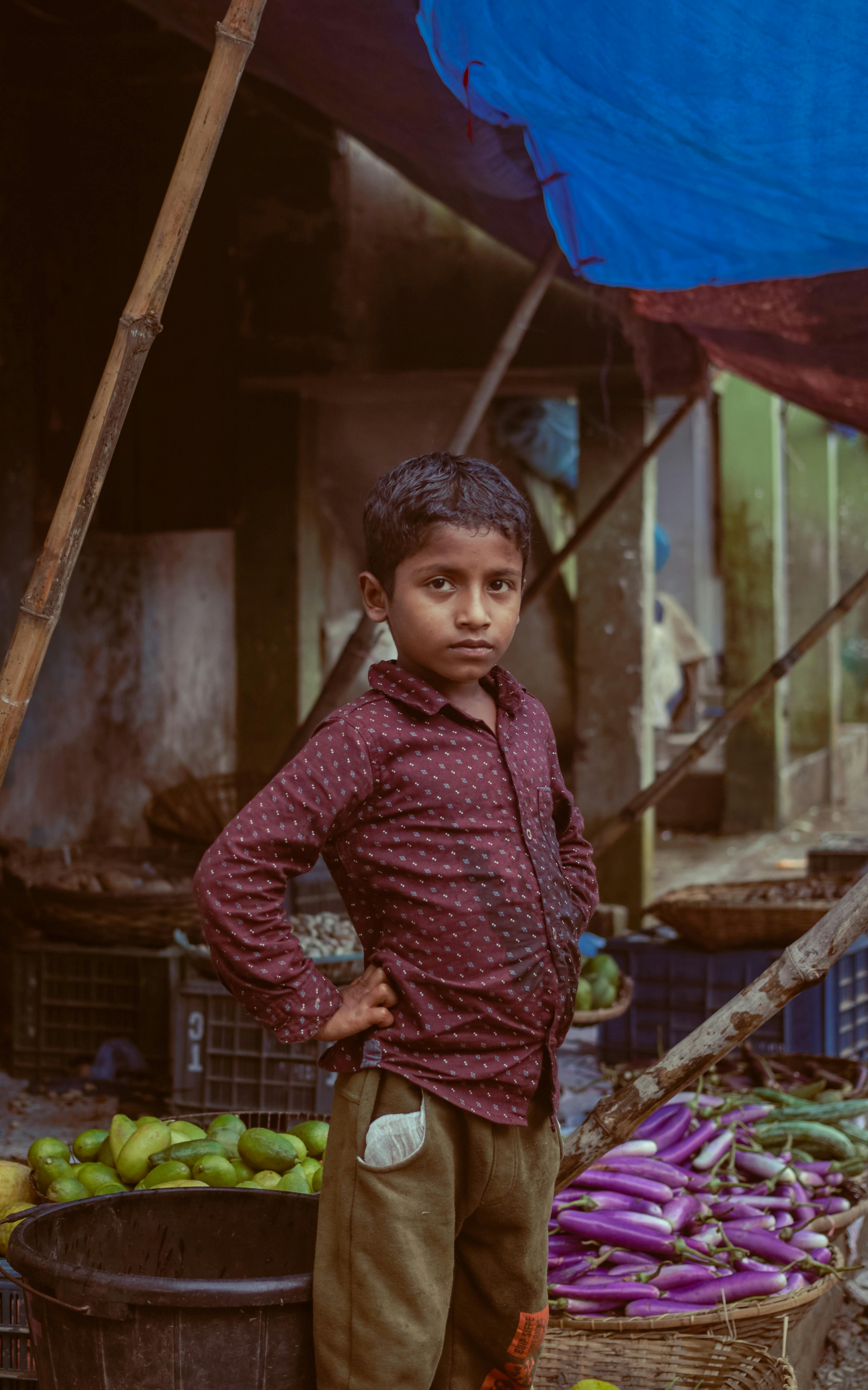 A Young Boy Standing at a Food Market · Free Stock Photo