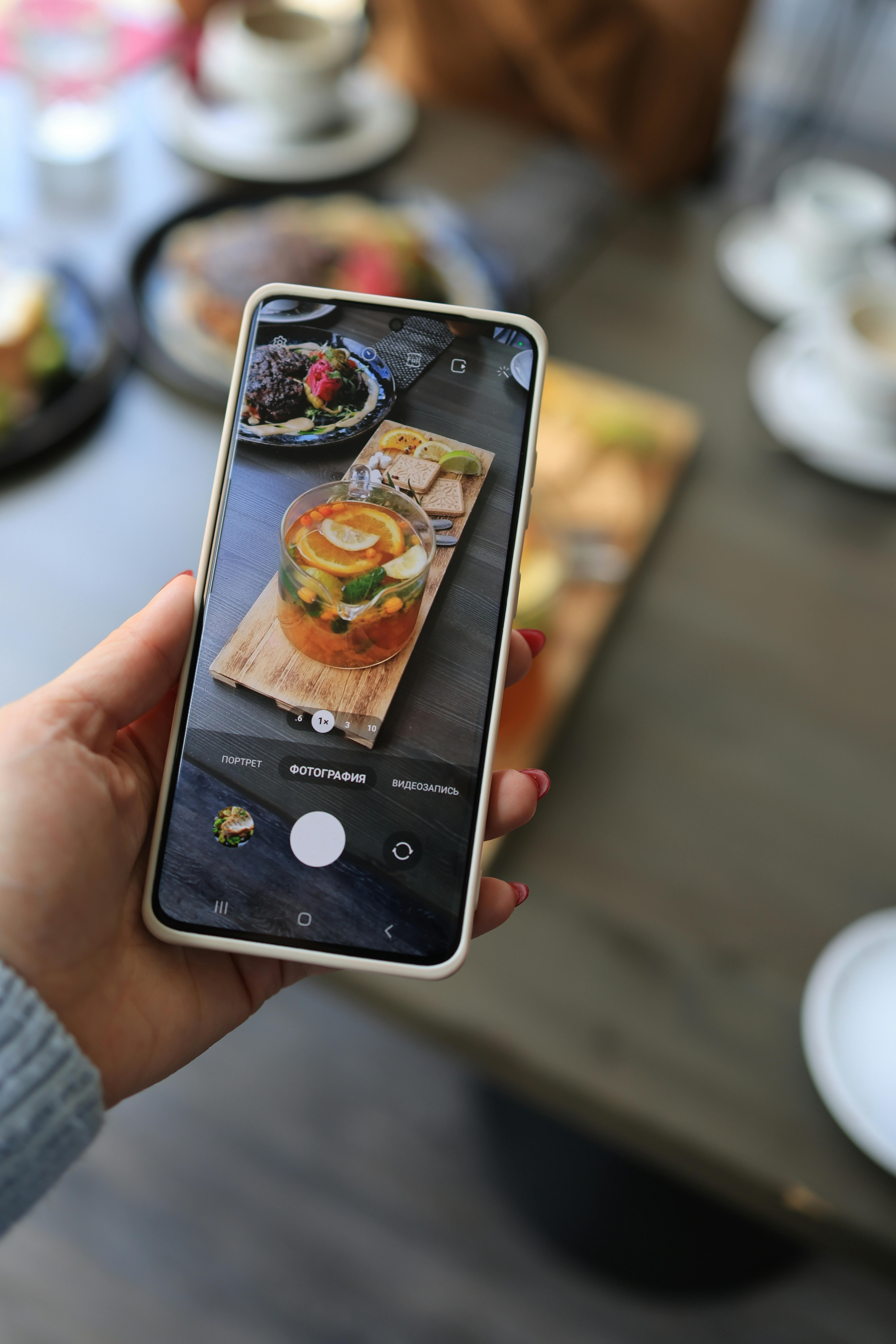 Hand Holding Cellphone and Taking Pictures of Tea in Cup · Free Stock Photo